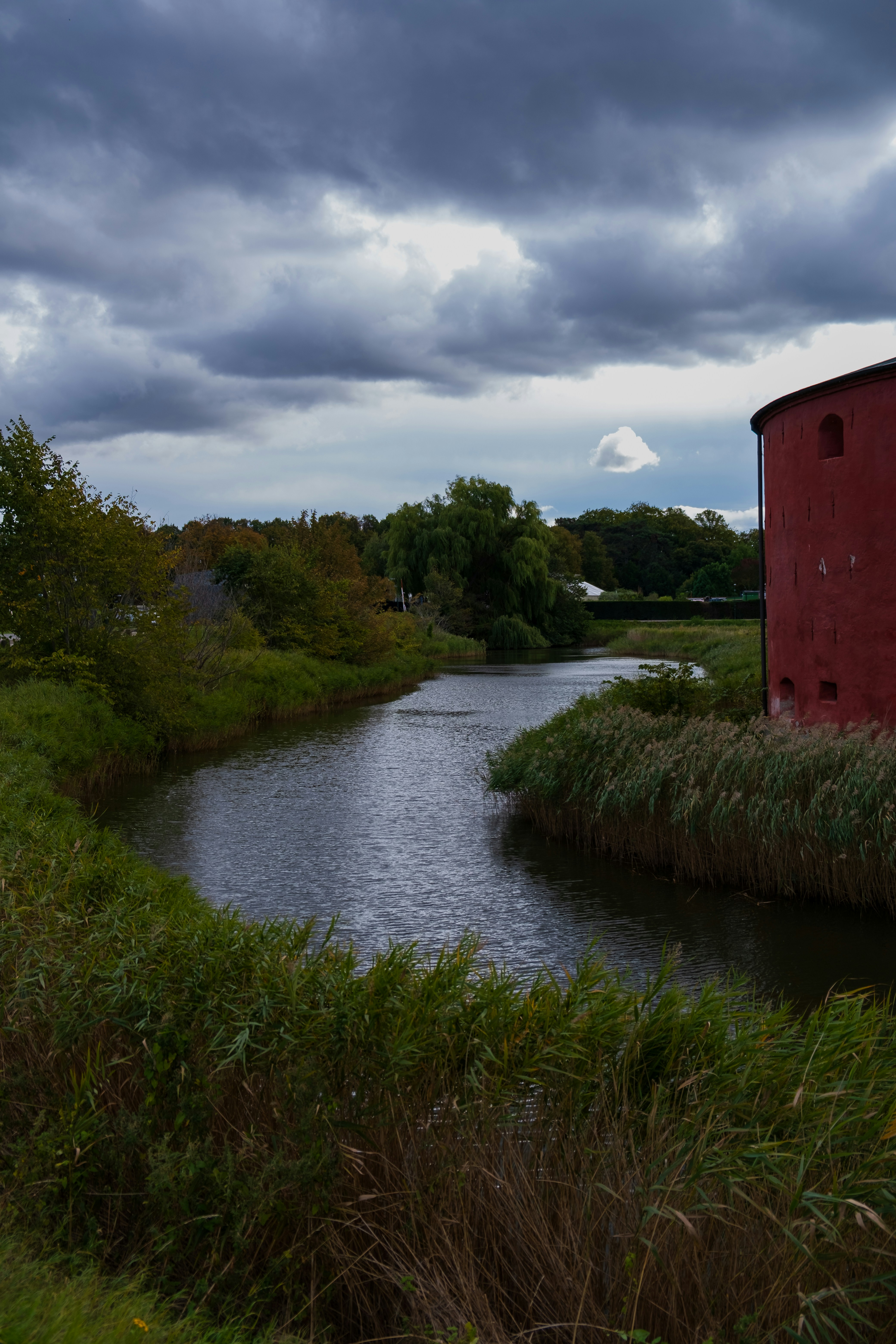 Crimson Turret by the River: Reeds, Clouds, and Quiet Light