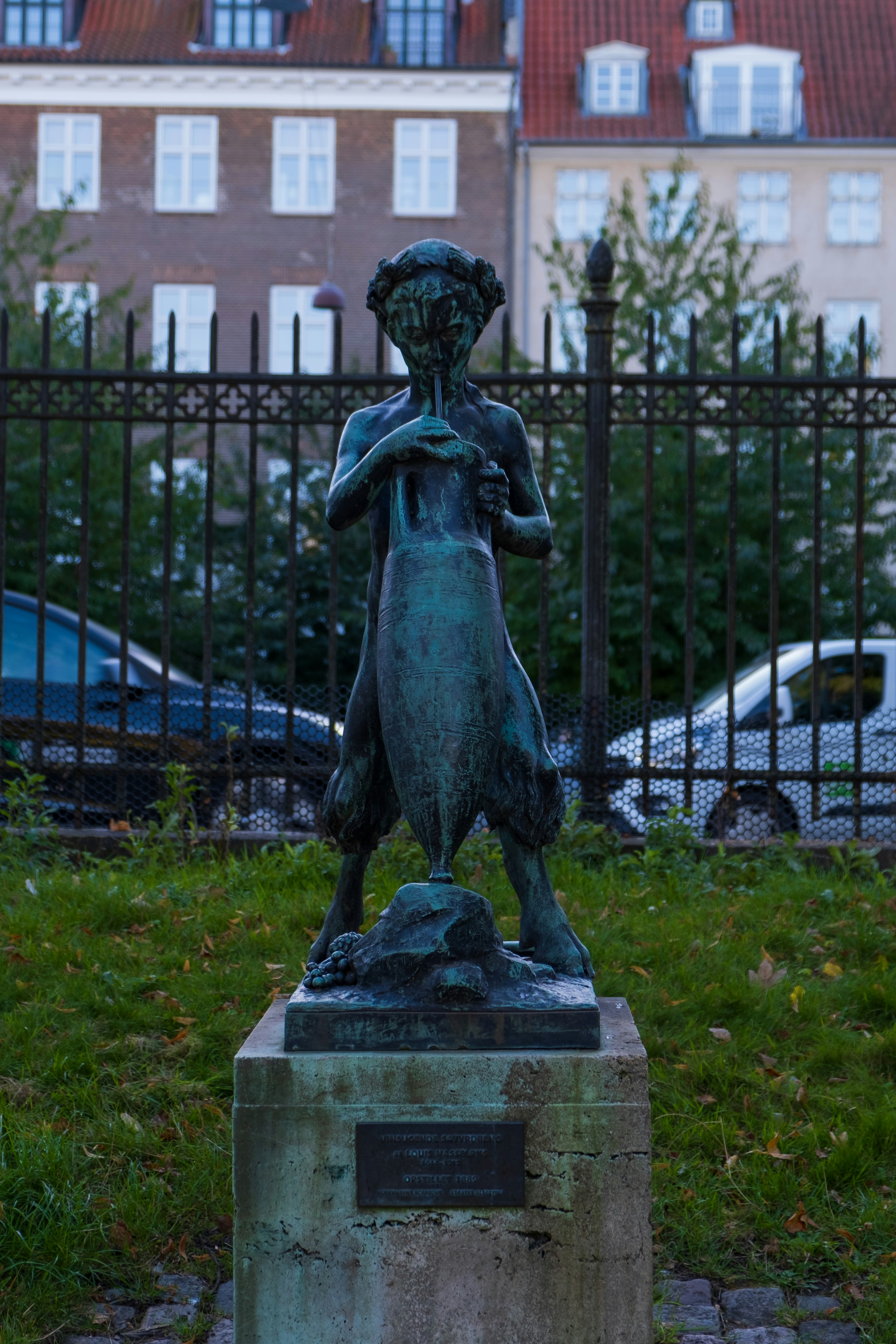 Patinaed Quiet: A Bronze Child Statue Framed by Cast Iron and Townhouses