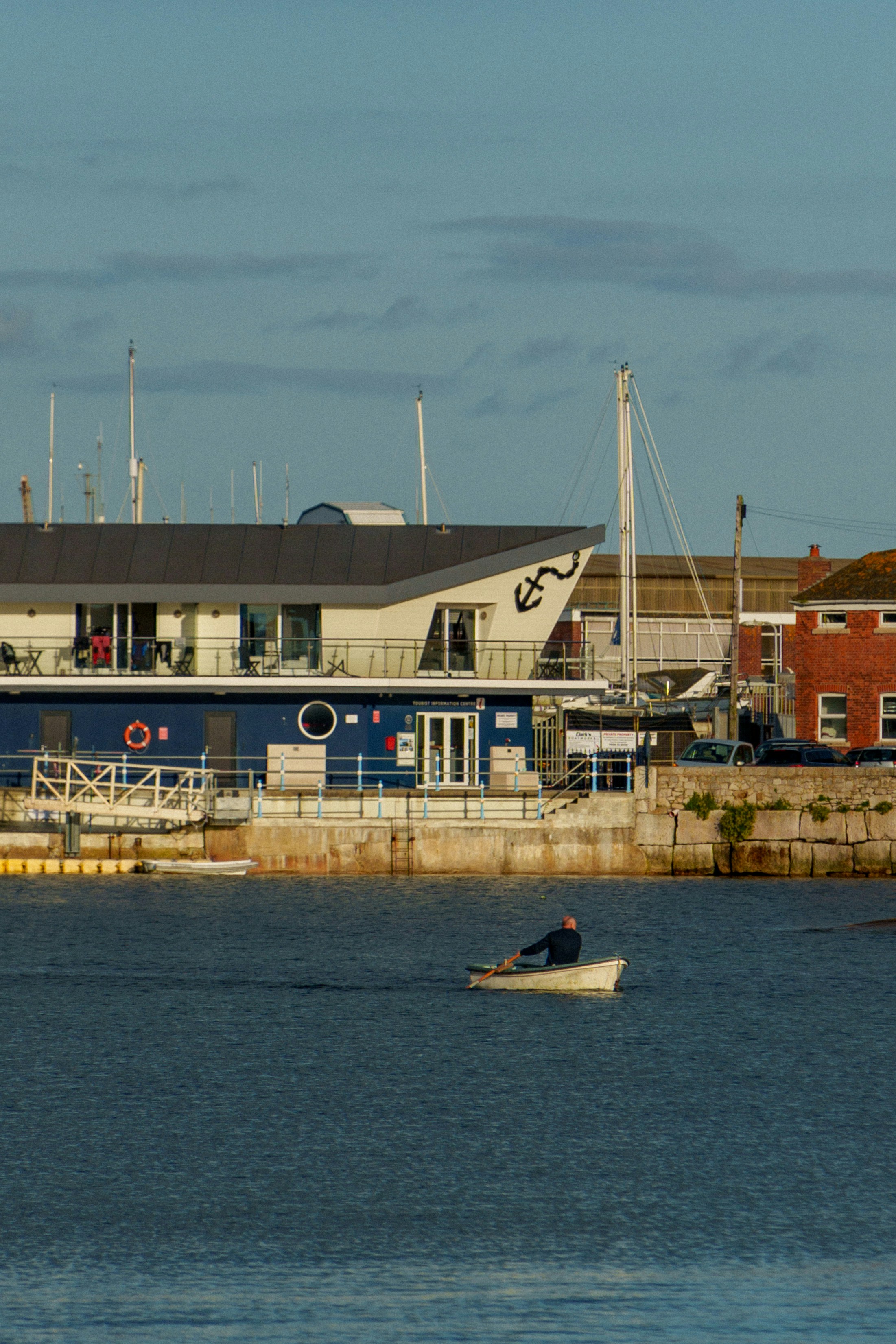 Skiff Drifts Past a Modern Marina on a Quiet Waterfront