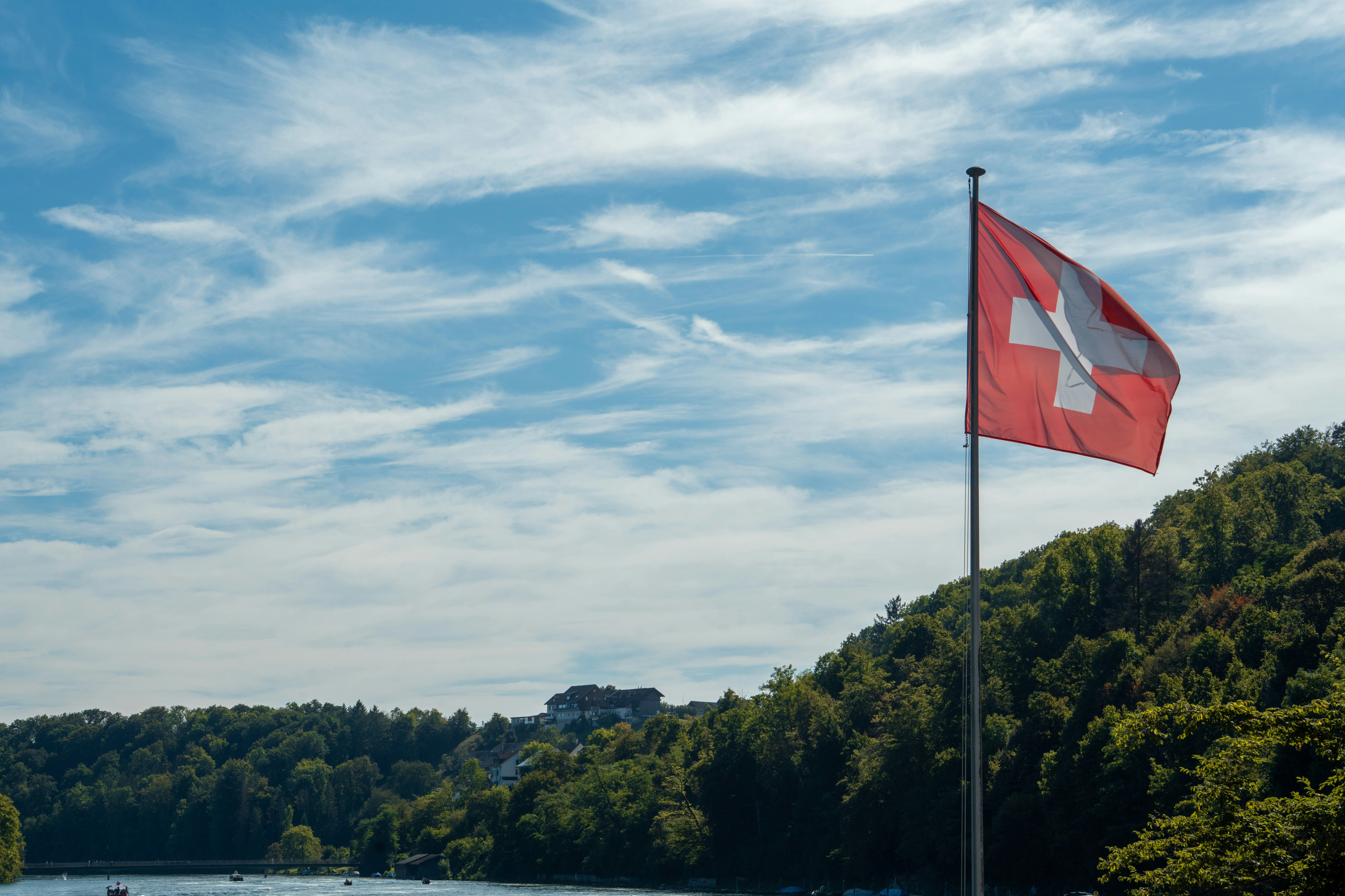 Flag Overlooking a Lake: A Swiss Emblem Against a Blue Sky