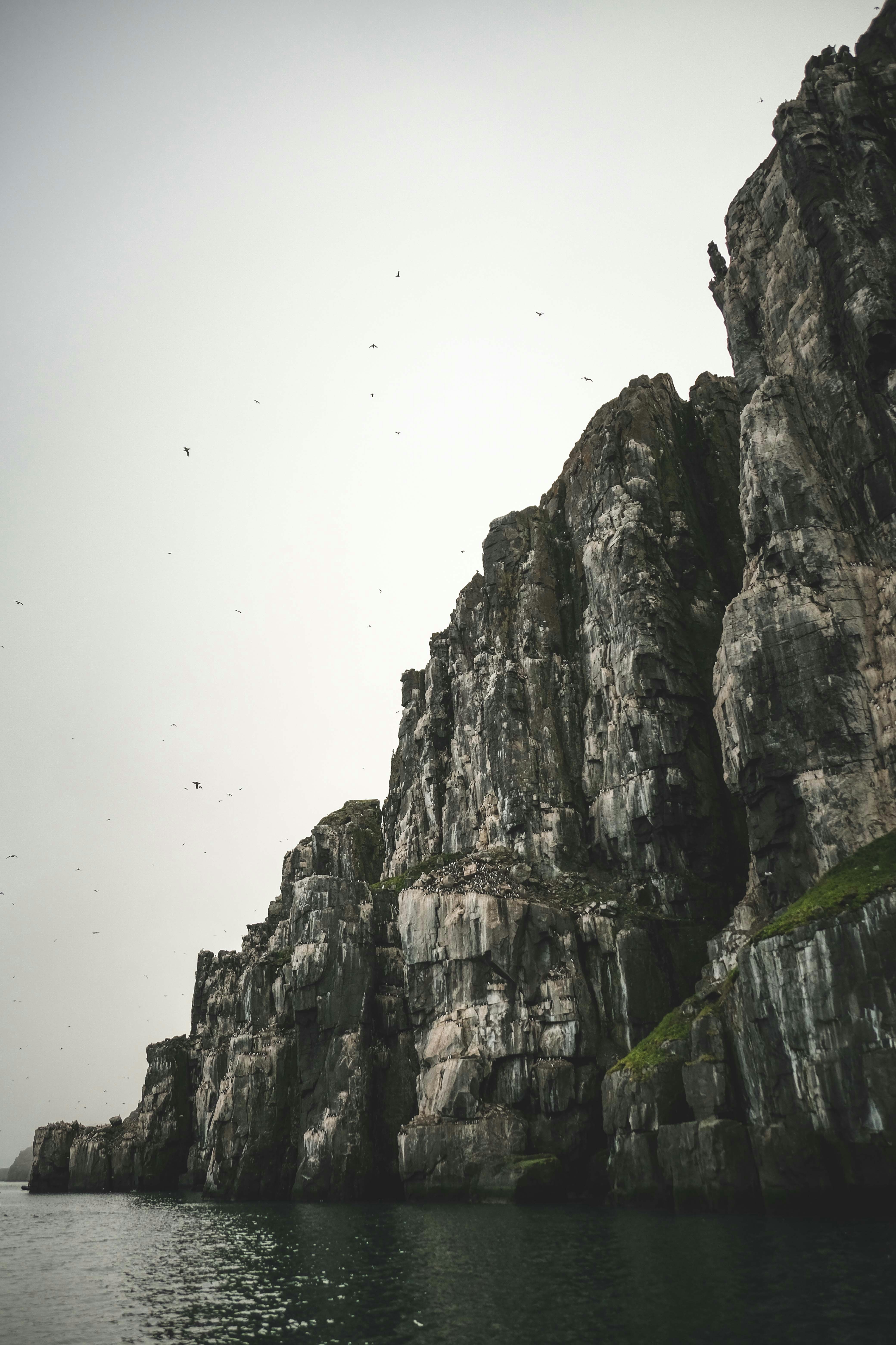 A large rock outcropping in the middle of a body of water photo – Free ...