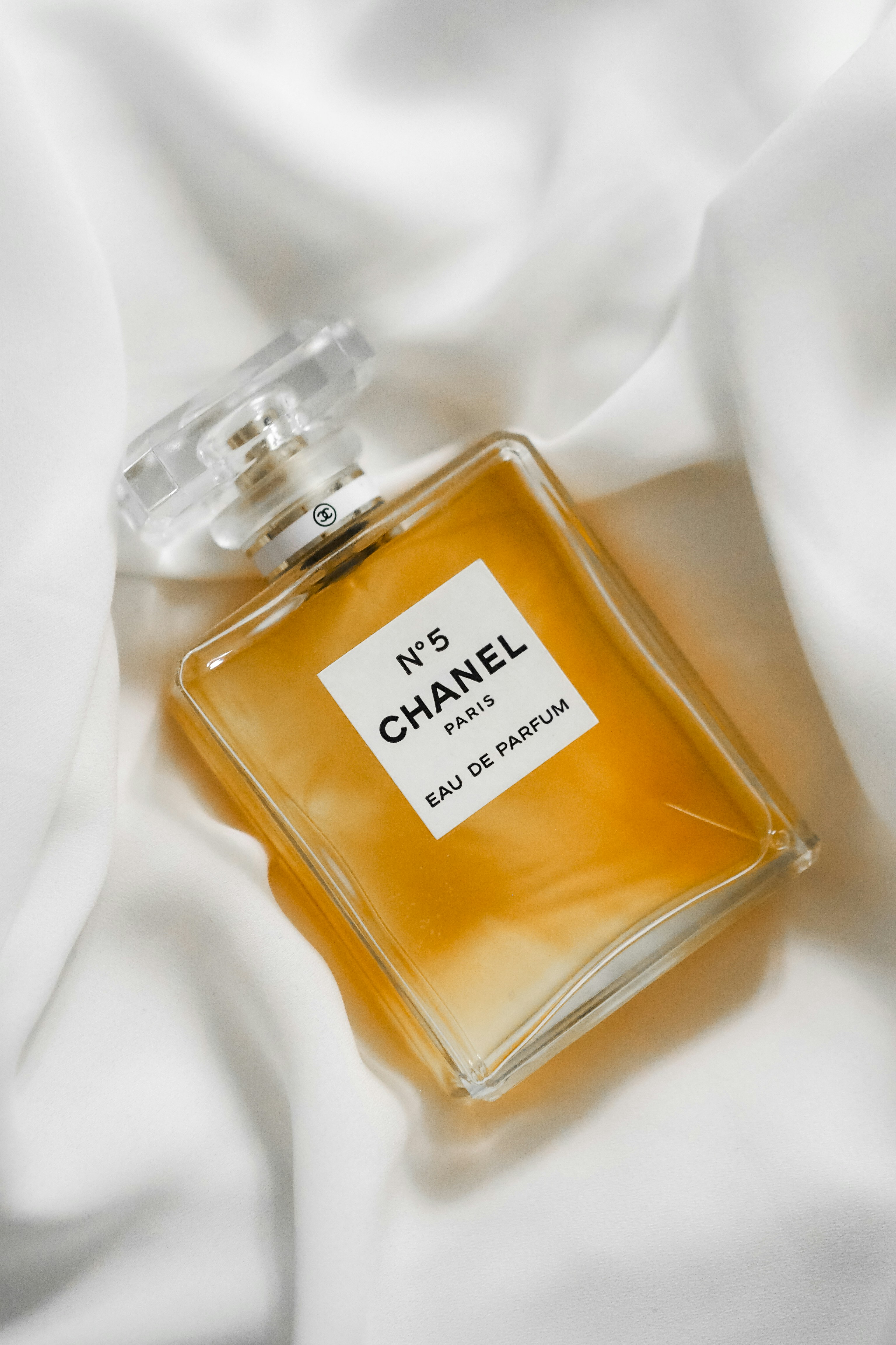 A bottle of chanel perfume sitting on a white sheet photo – Free Style ...