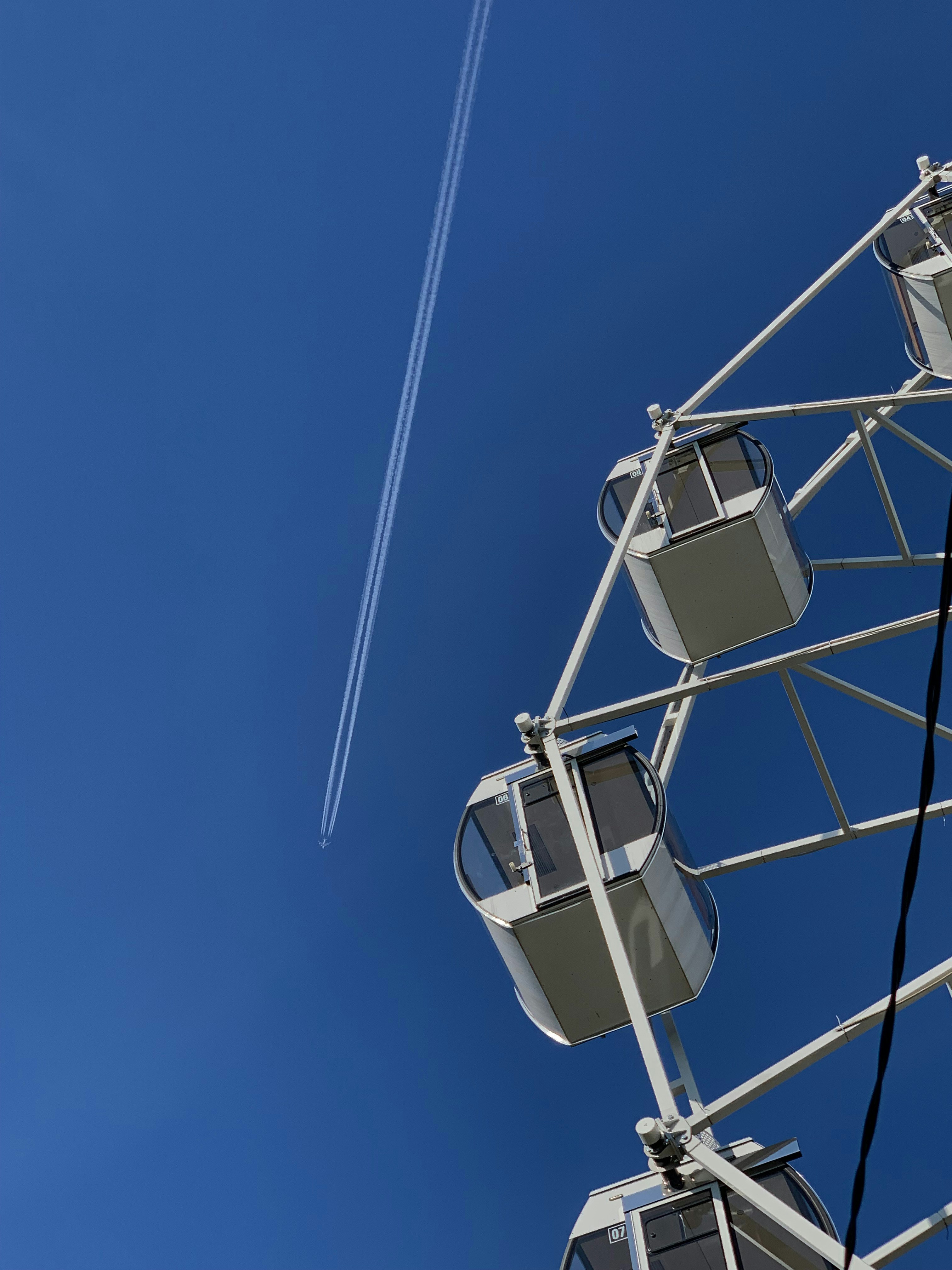 Contrail Over the Ferris Wheel: Steel Circles in a Blue Expanse
