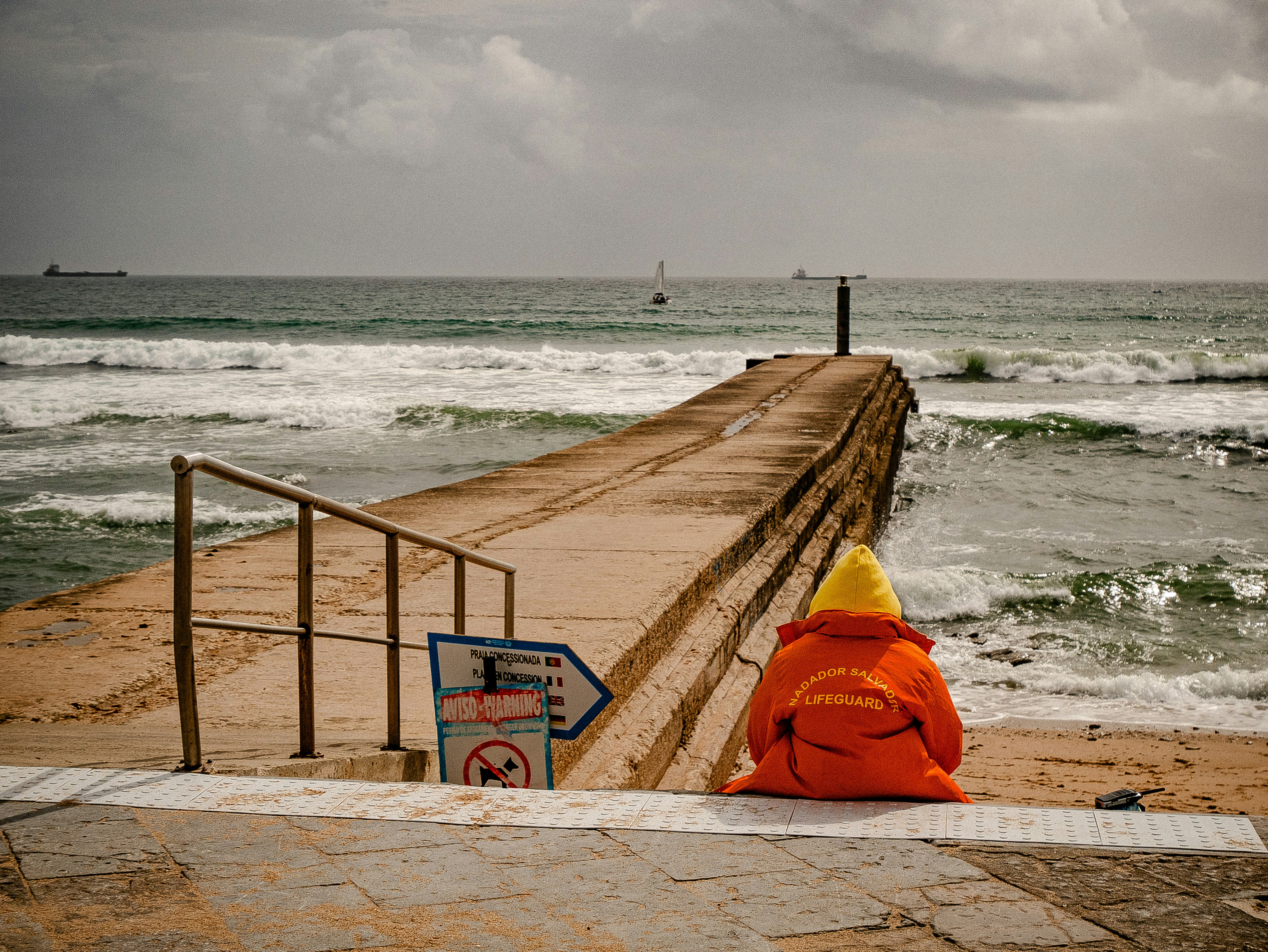 Orange-clad silhouette at the wind-worn pier's edge