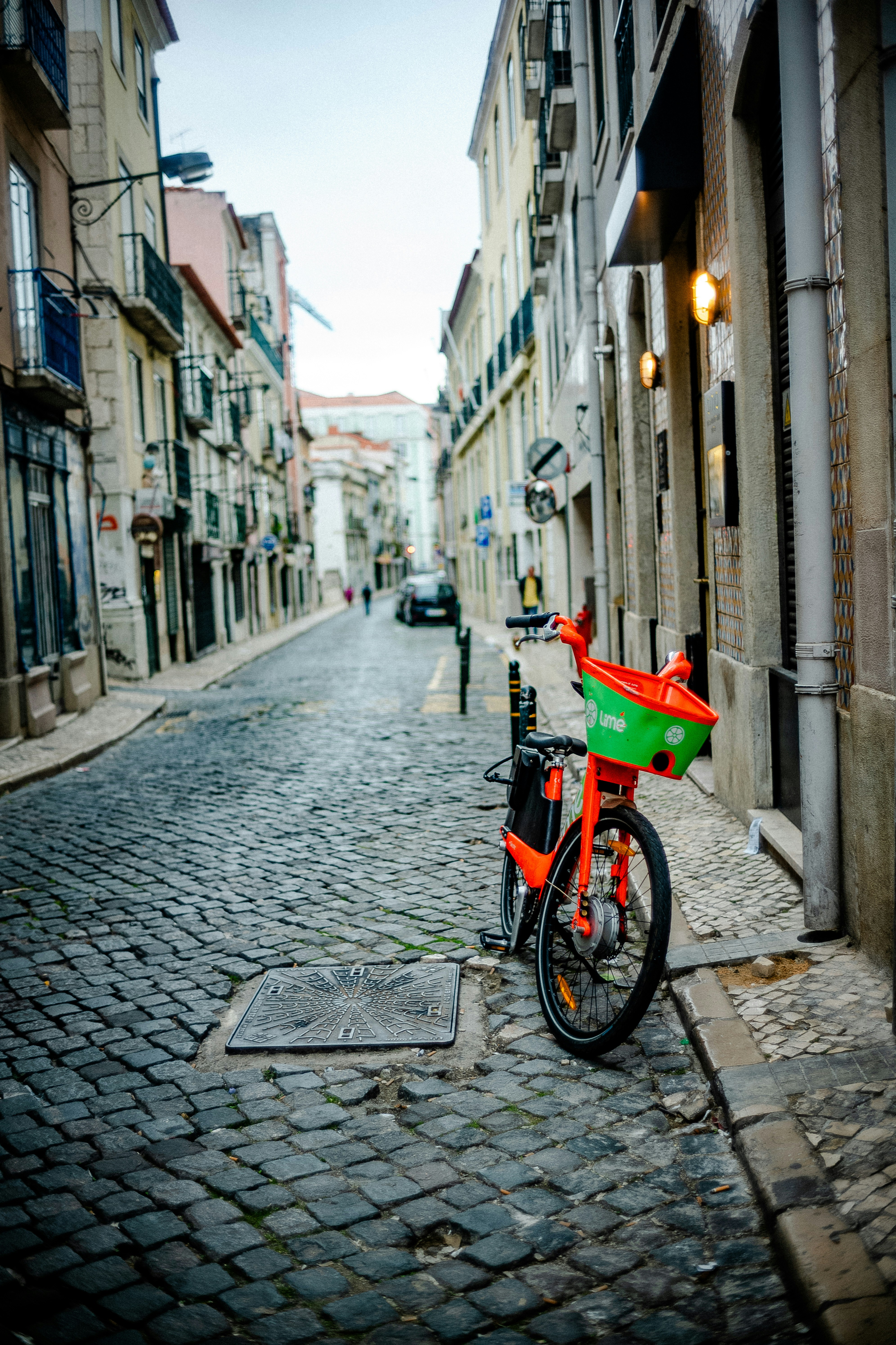Lime cargo bike anchors a sunlit cobblestone alley