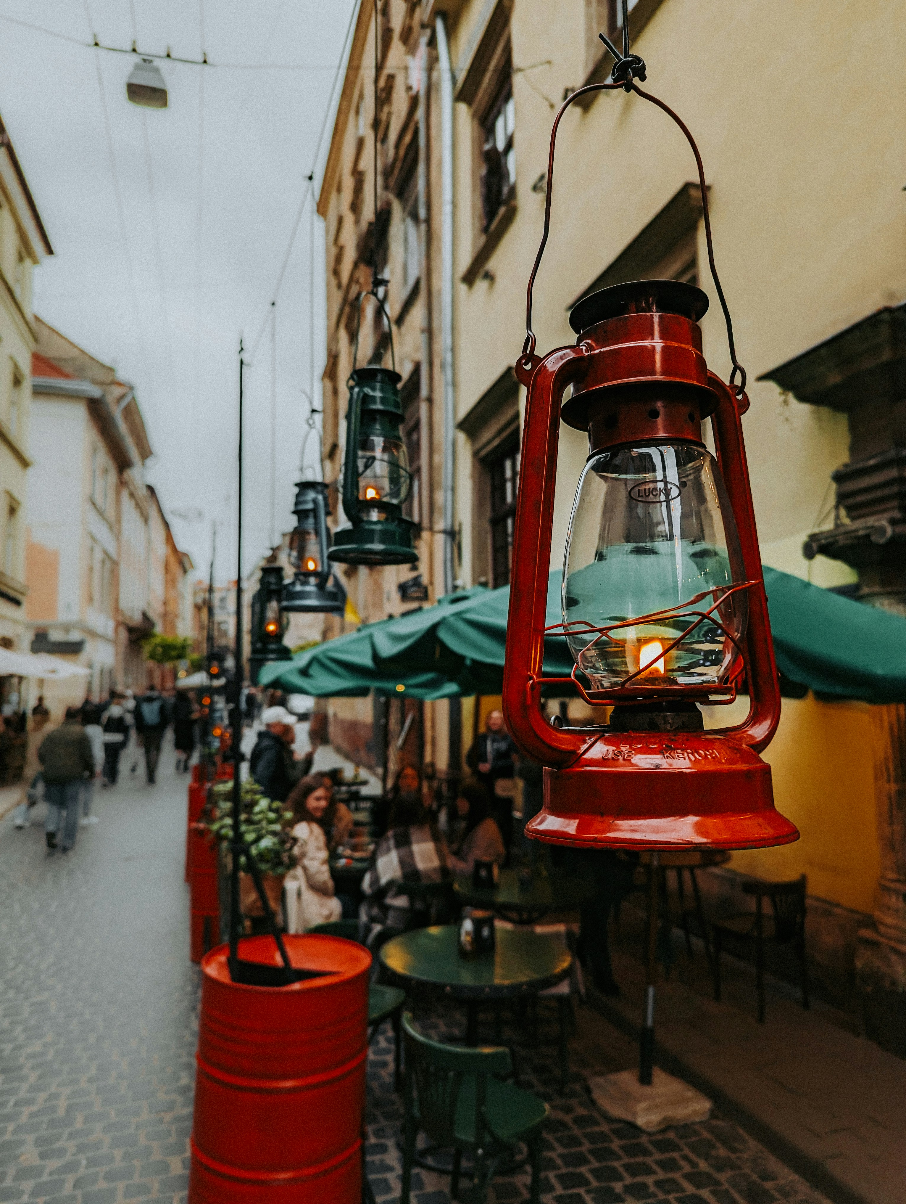 Crimson Lanterns Framing a Café-Filled Cobbled Street