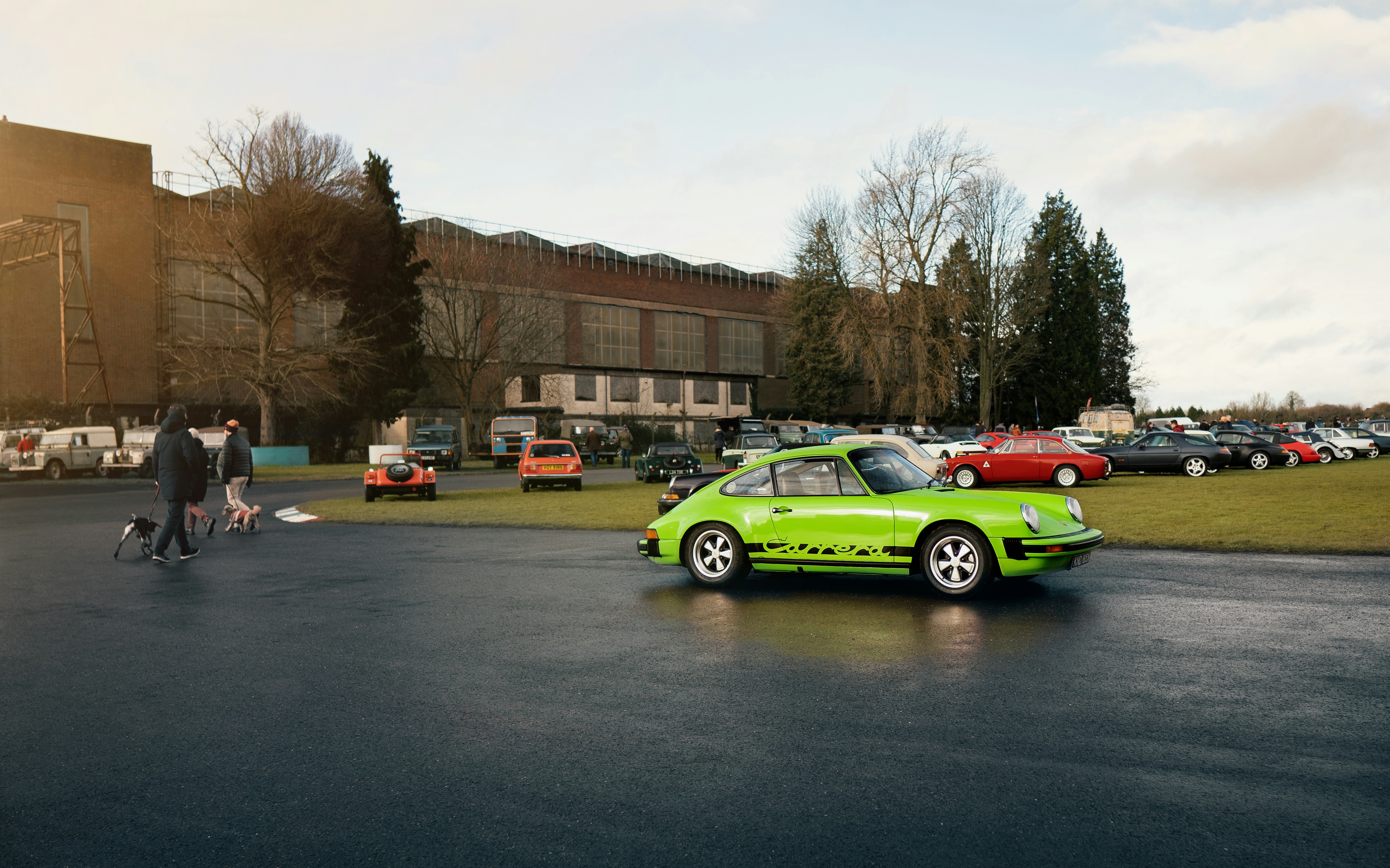 A green car driving down a street next to a tall building photo – Free ...