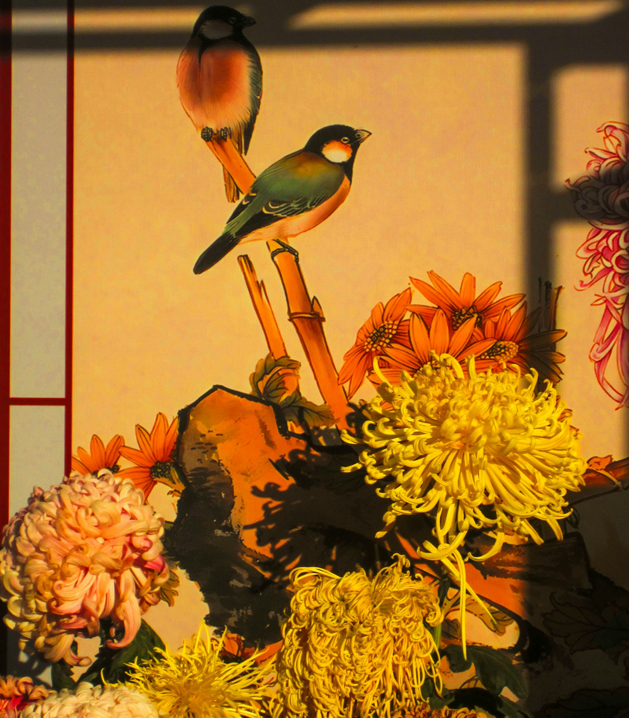 Two kingfishers perch among bright chrysanthemums on a warm-toned painting, creating a decorative focal point.