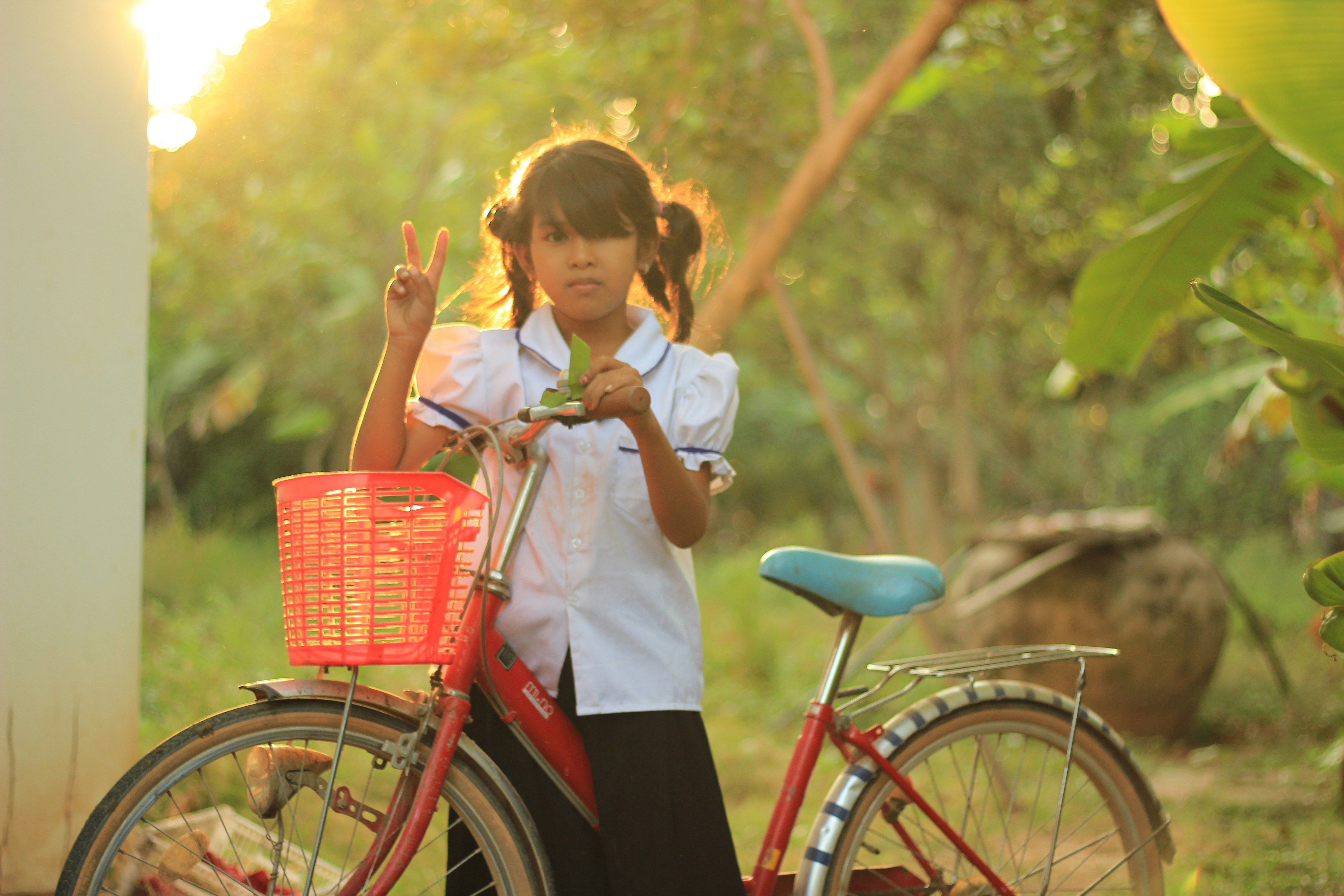 赤い自転車の隣に立つ少女の写真 – Unsplashの女の子の無料画像
