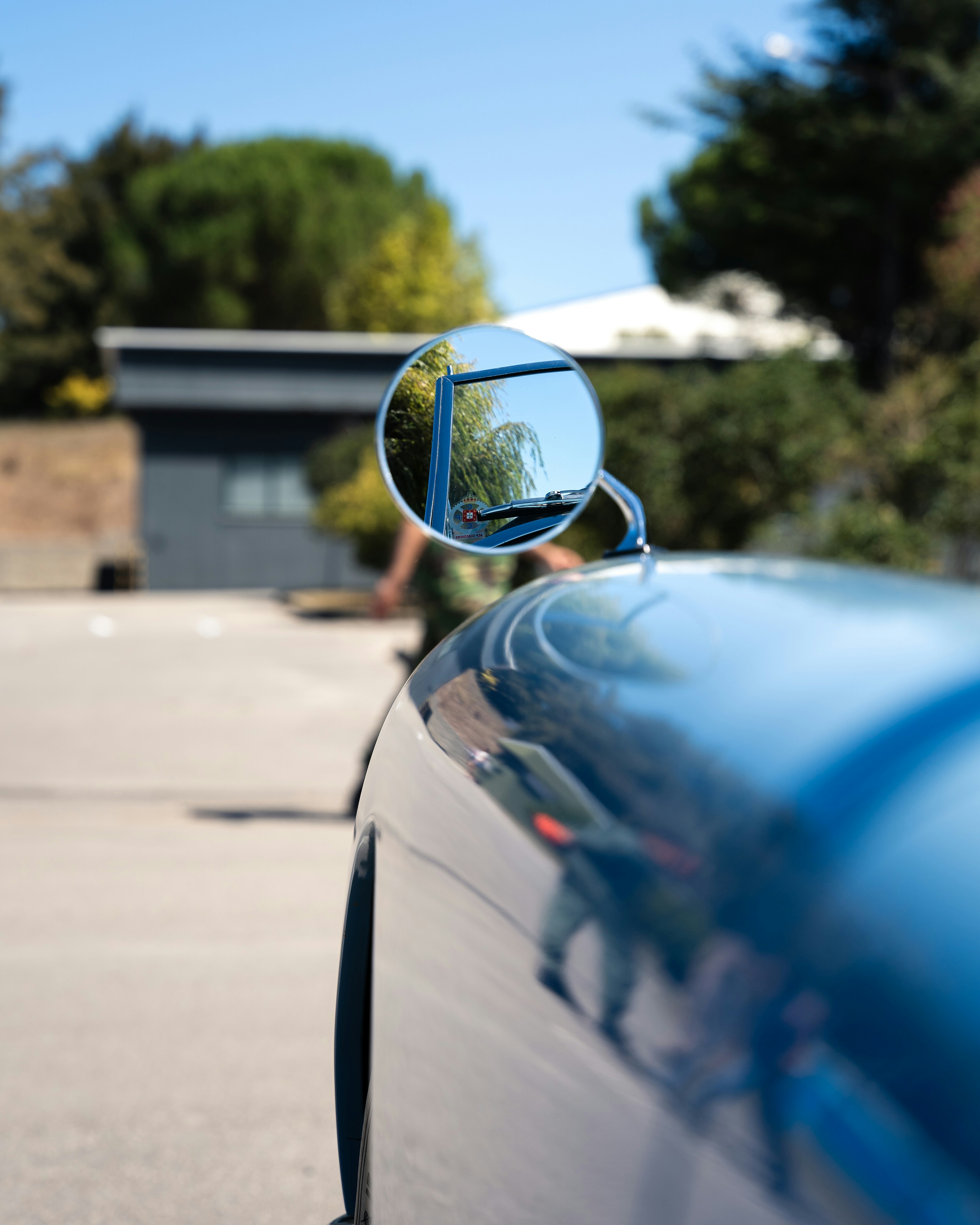 Convex Mirror Echo: A Blue Car Through a Side-View Reflection