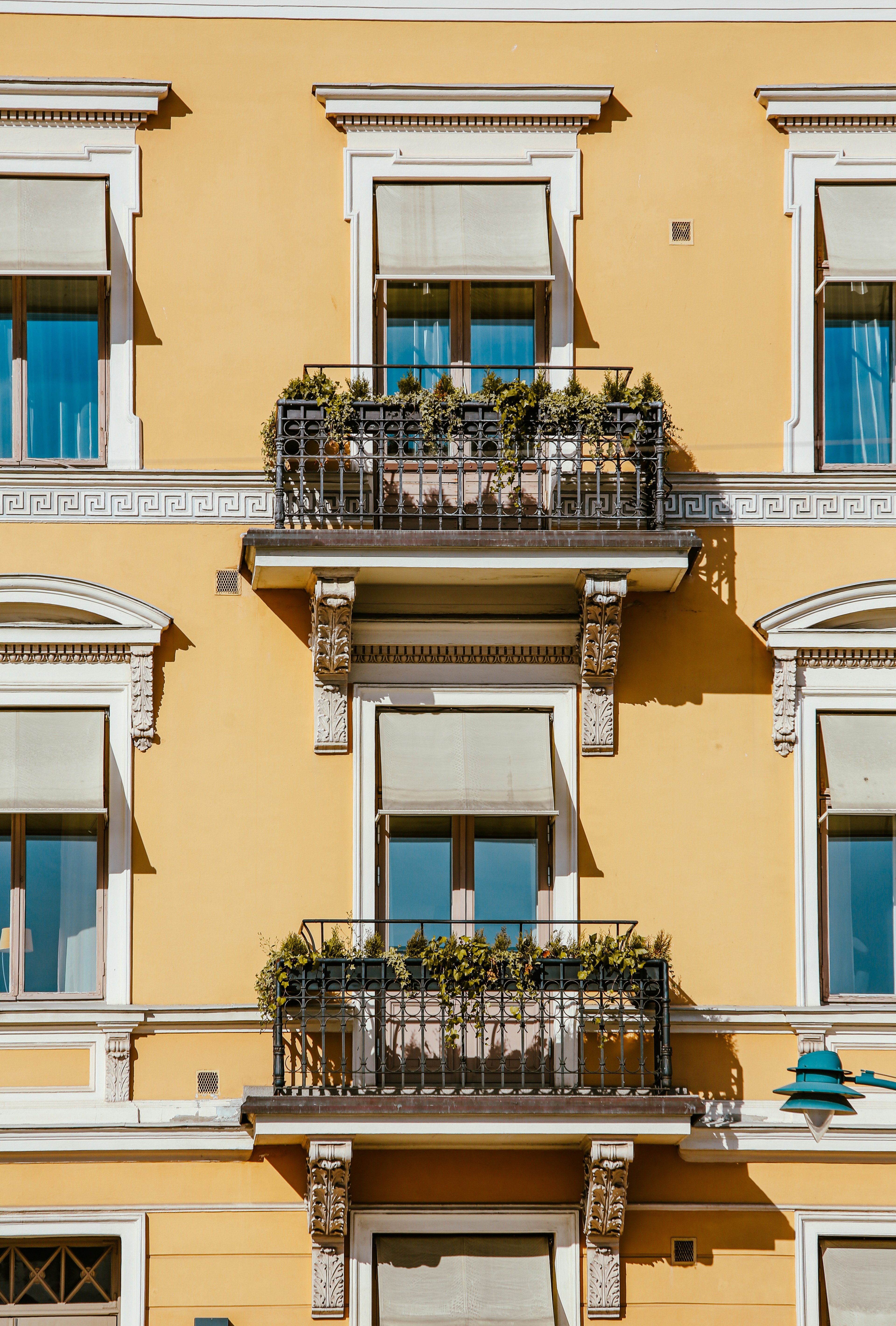 A tall yellow building with balconies and windows photo – Free Window ...