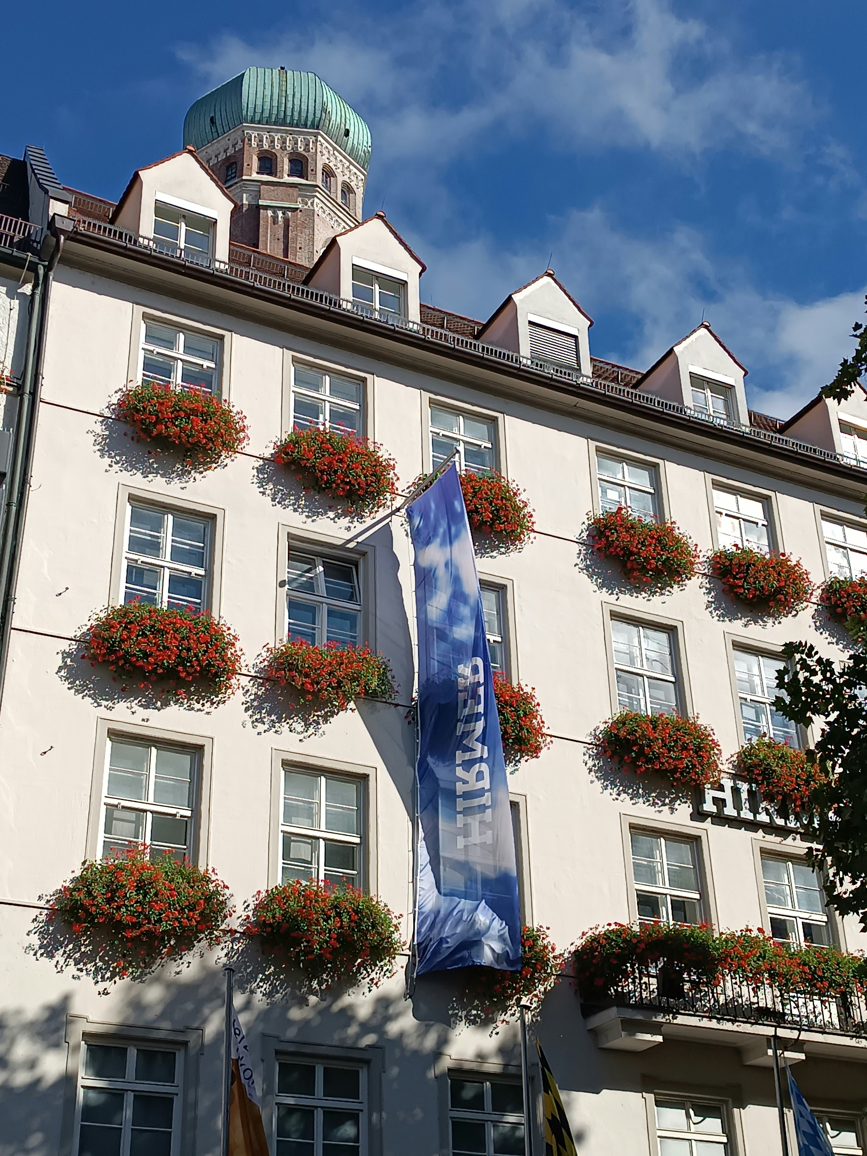 Floral Facade: A European Hotel With Hanging Blooms and a Blue Banner