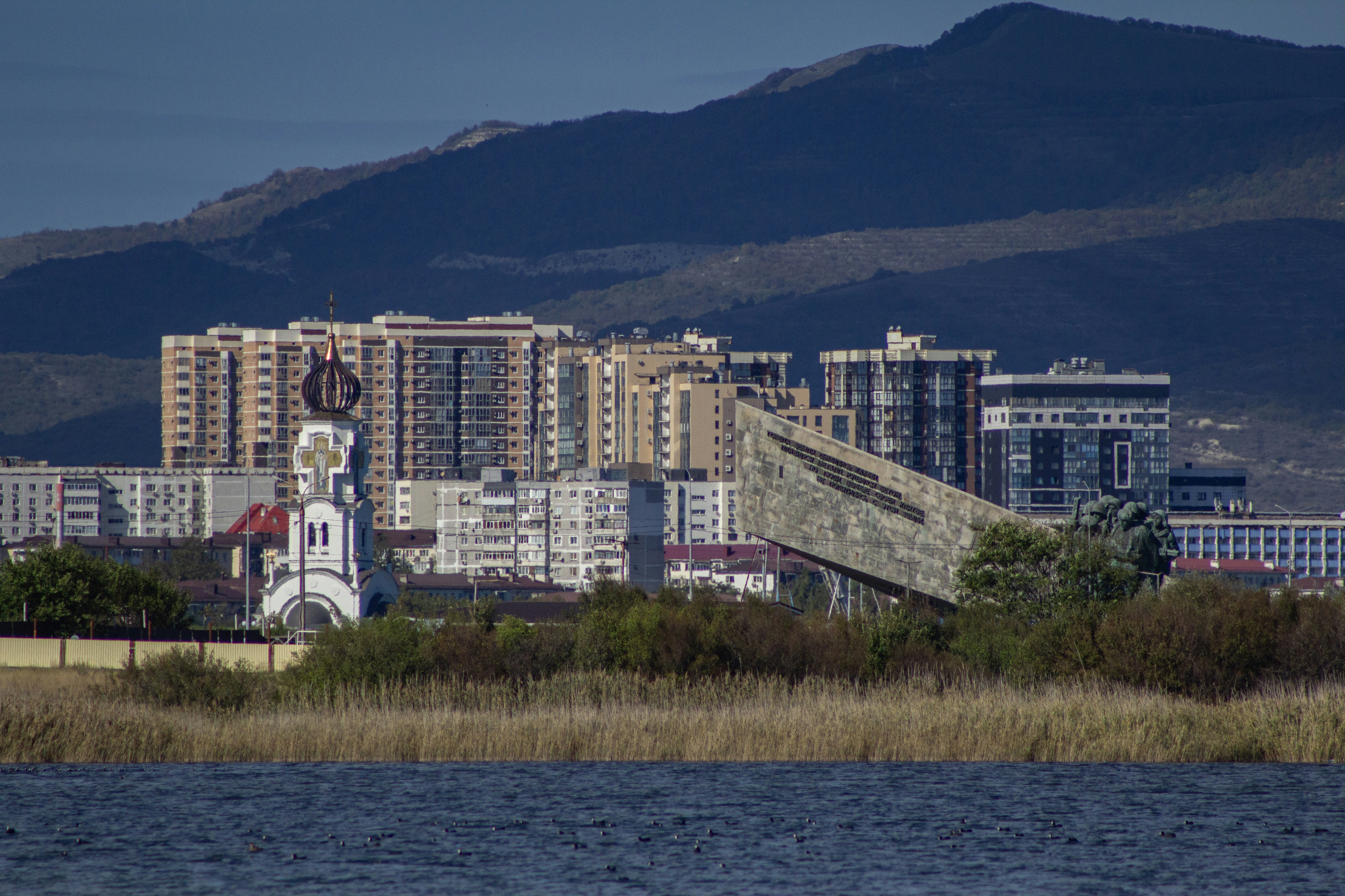 Spire and Skyline: Lakeside City Against Mountain Backdrop