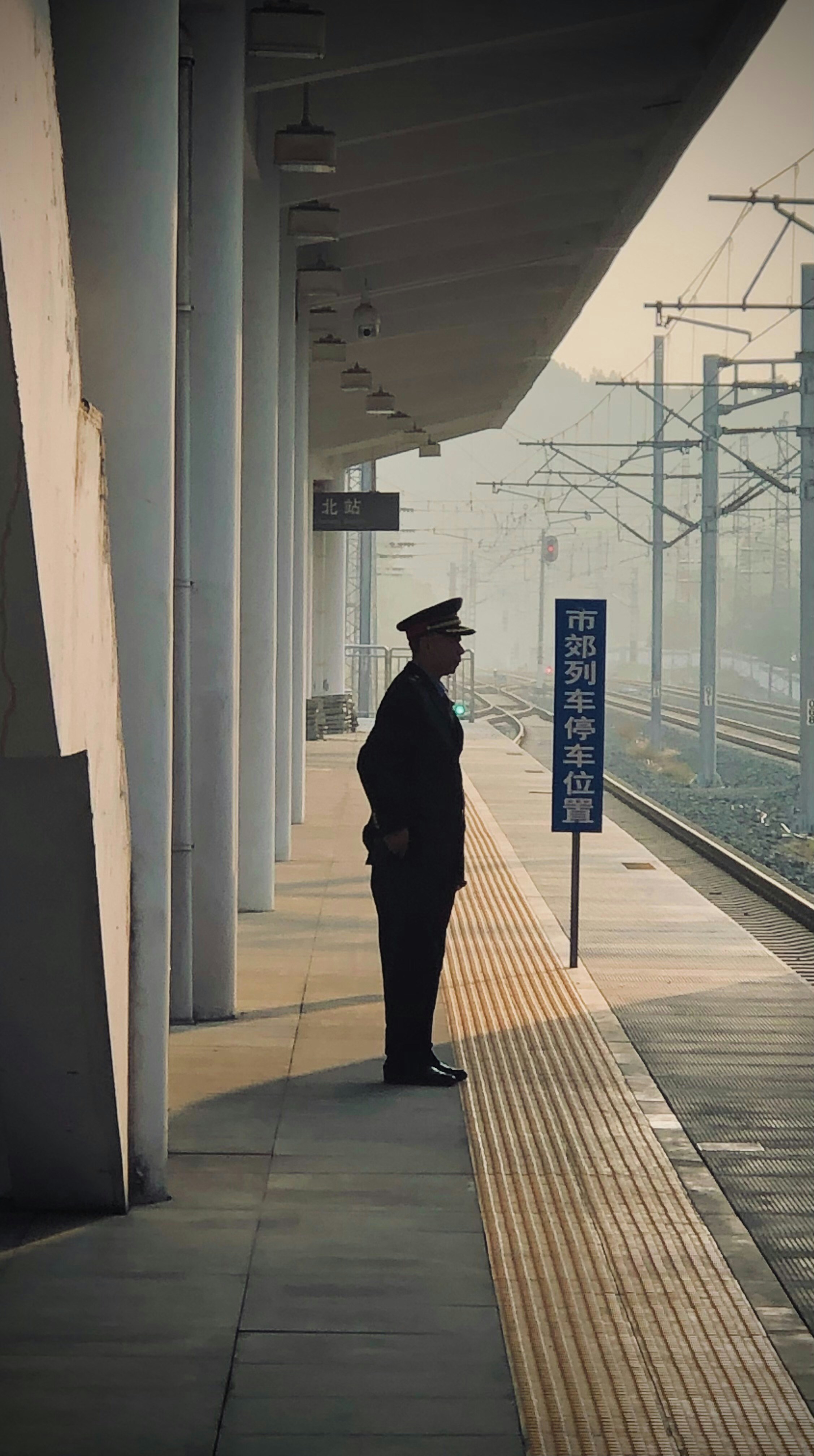 A man standing on a train platform next to a train photo – Free Man ...