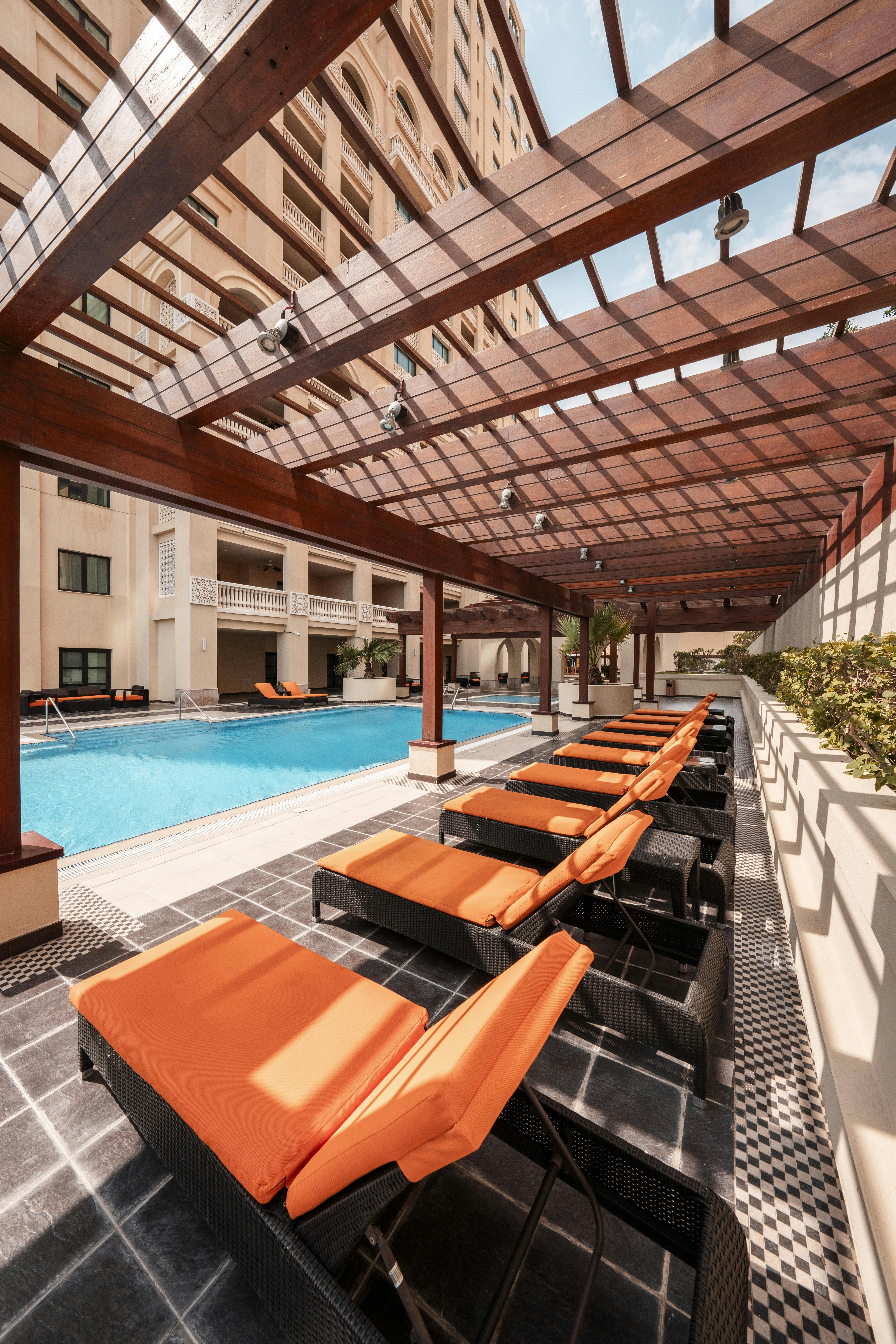 Ember Cushions by a Glass-Canopy Pool: A Sun-Drenched Lounge Row