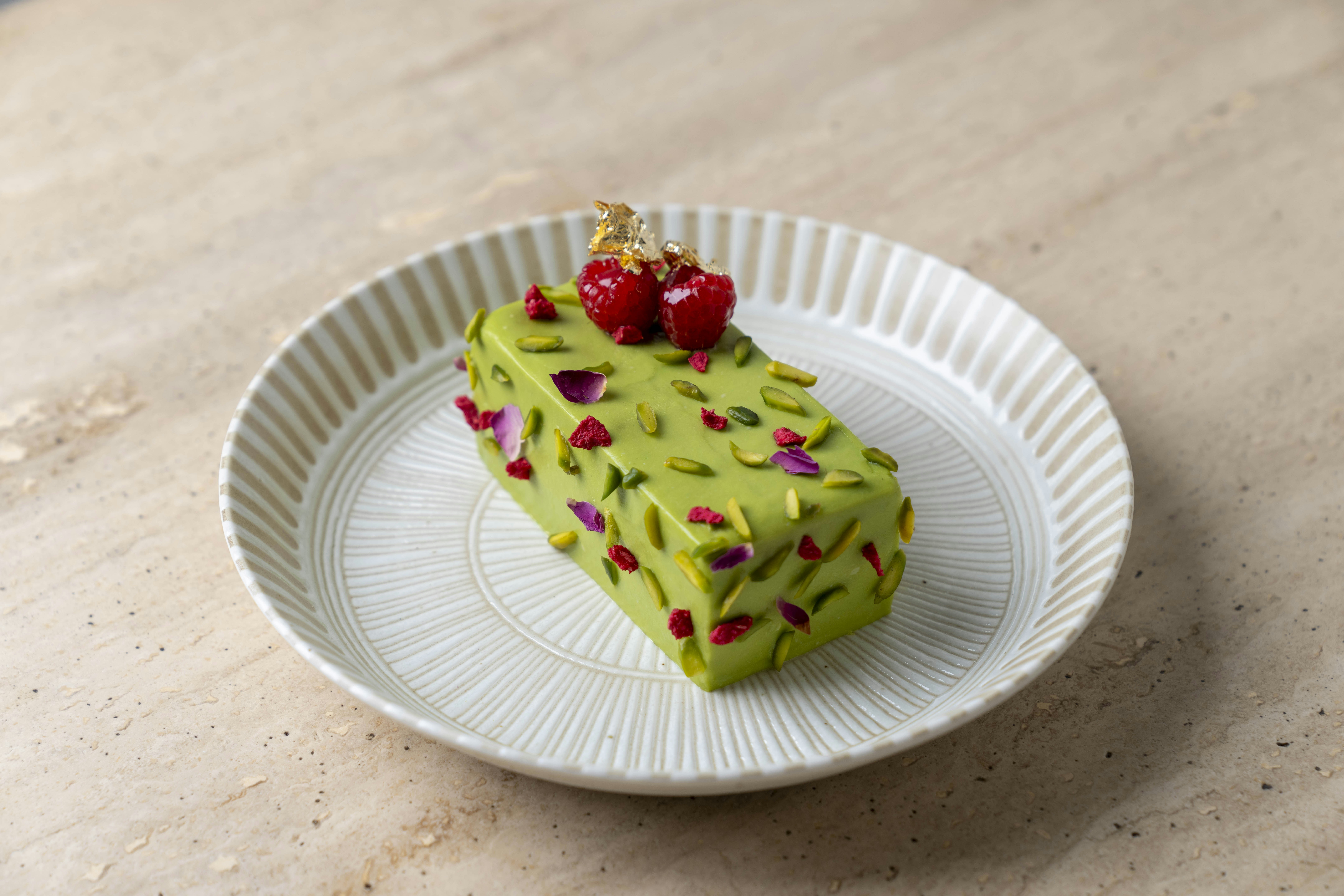 Lime-green Rectangular Pastry with Red Garnish rests on a ribbed plate