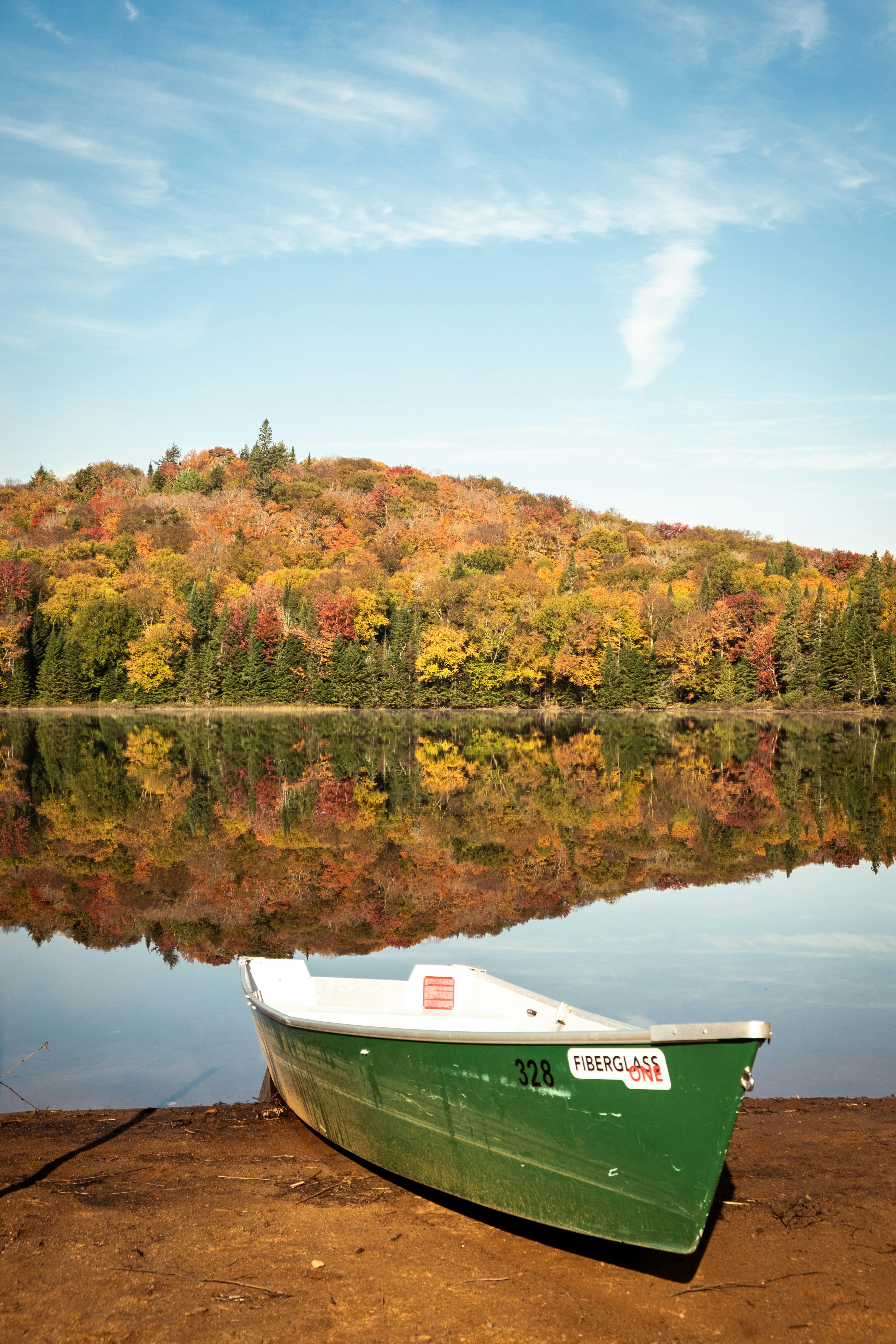 Emerald Skiff at Autumn's Edge: Reflections on a Quiet Lake