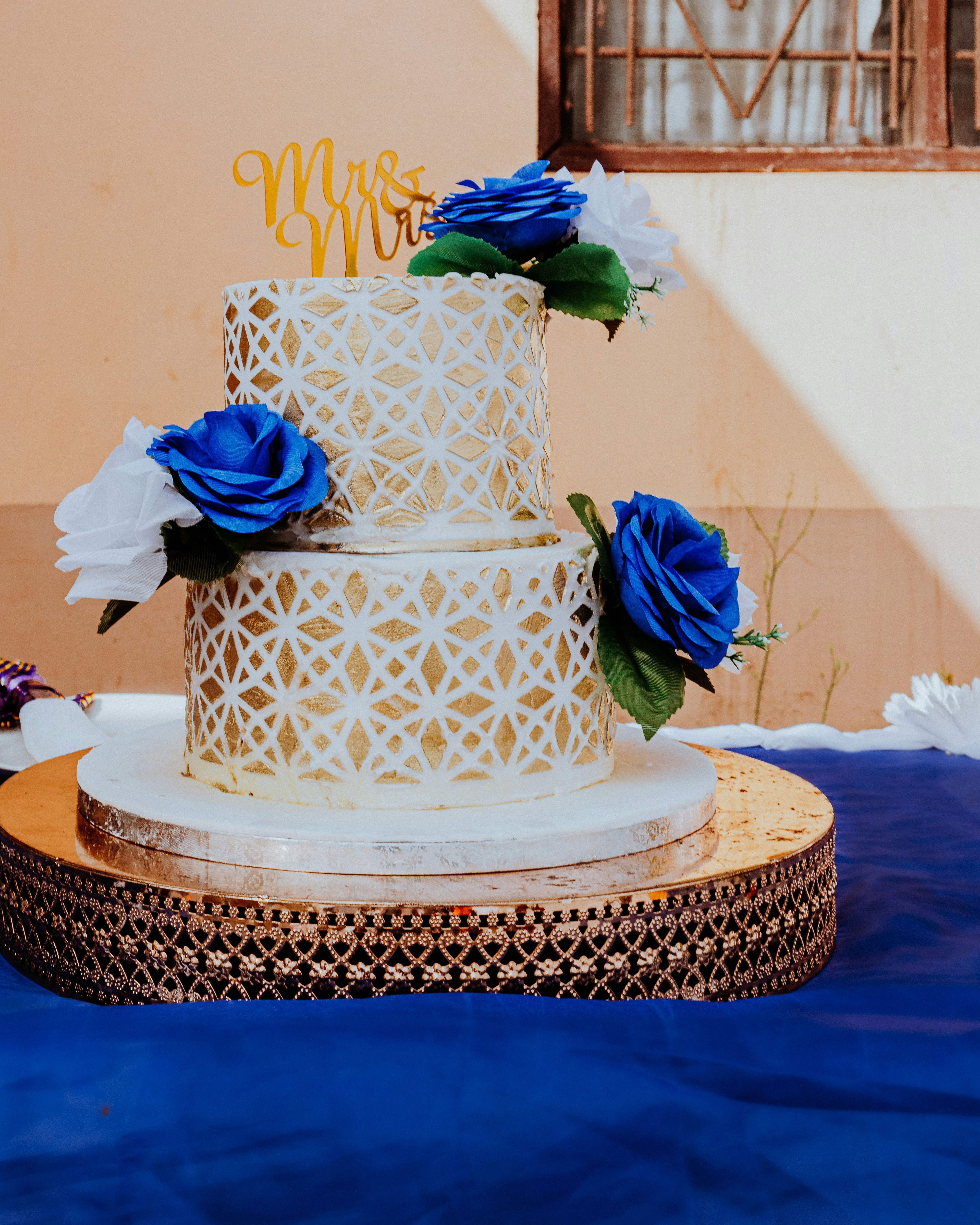 Cobalt Roses Crown a Geometric Wedding Cake on a Golden Pedestal
