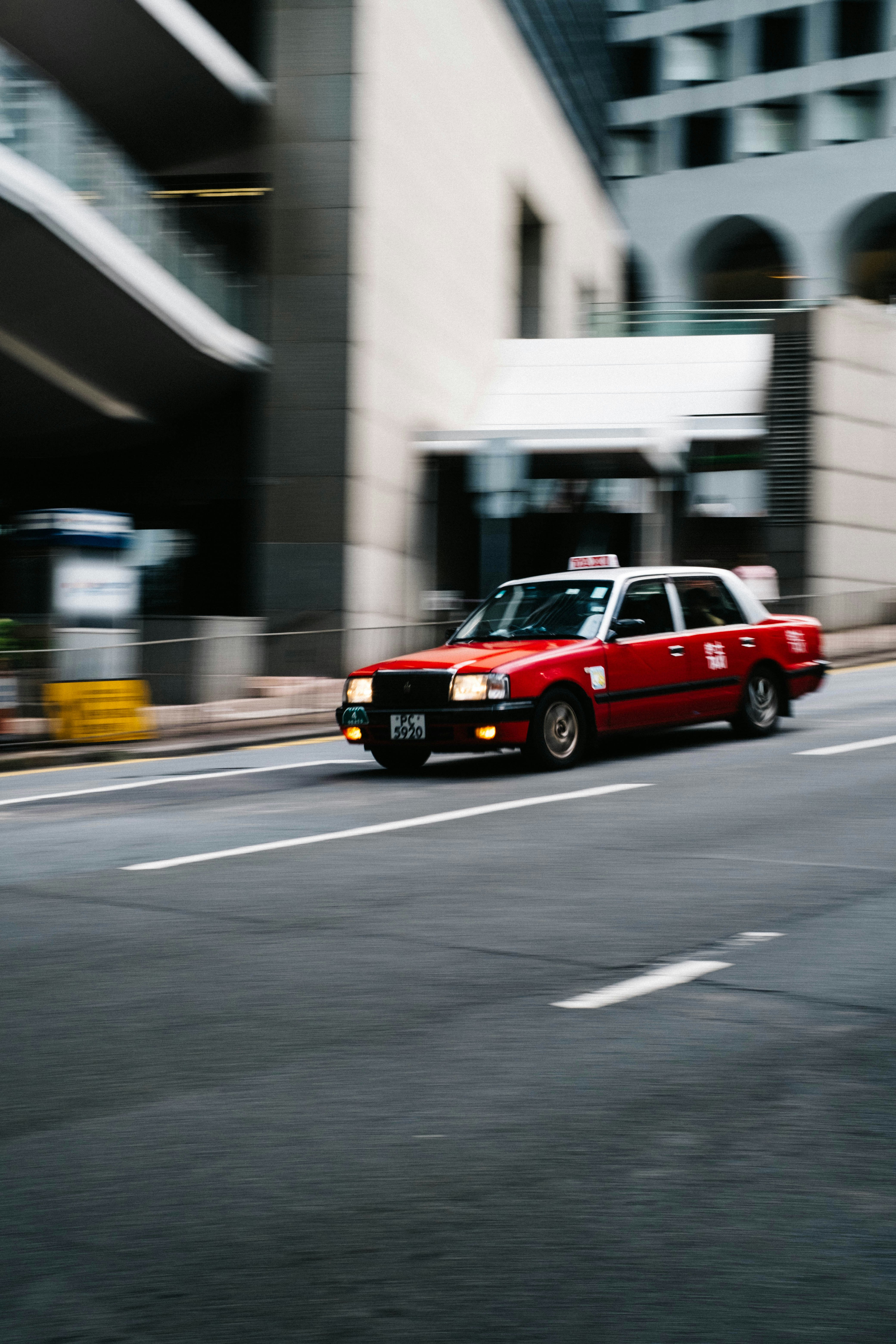 A red taxi cab driving down a street next to tall buildings photo ...