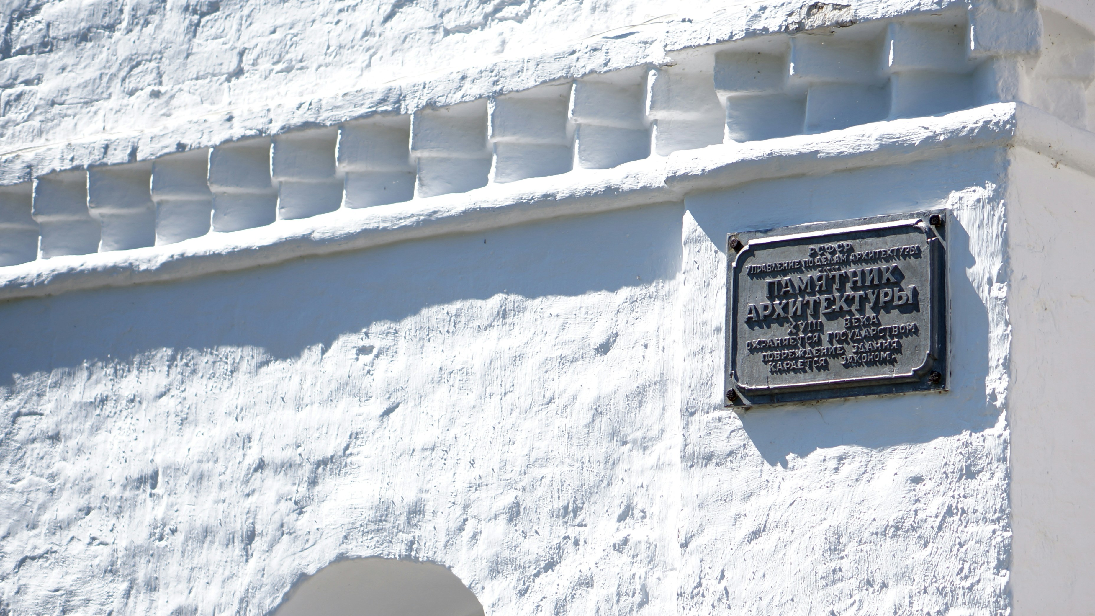 A Weathered Plaque on a Sunlit White Facade