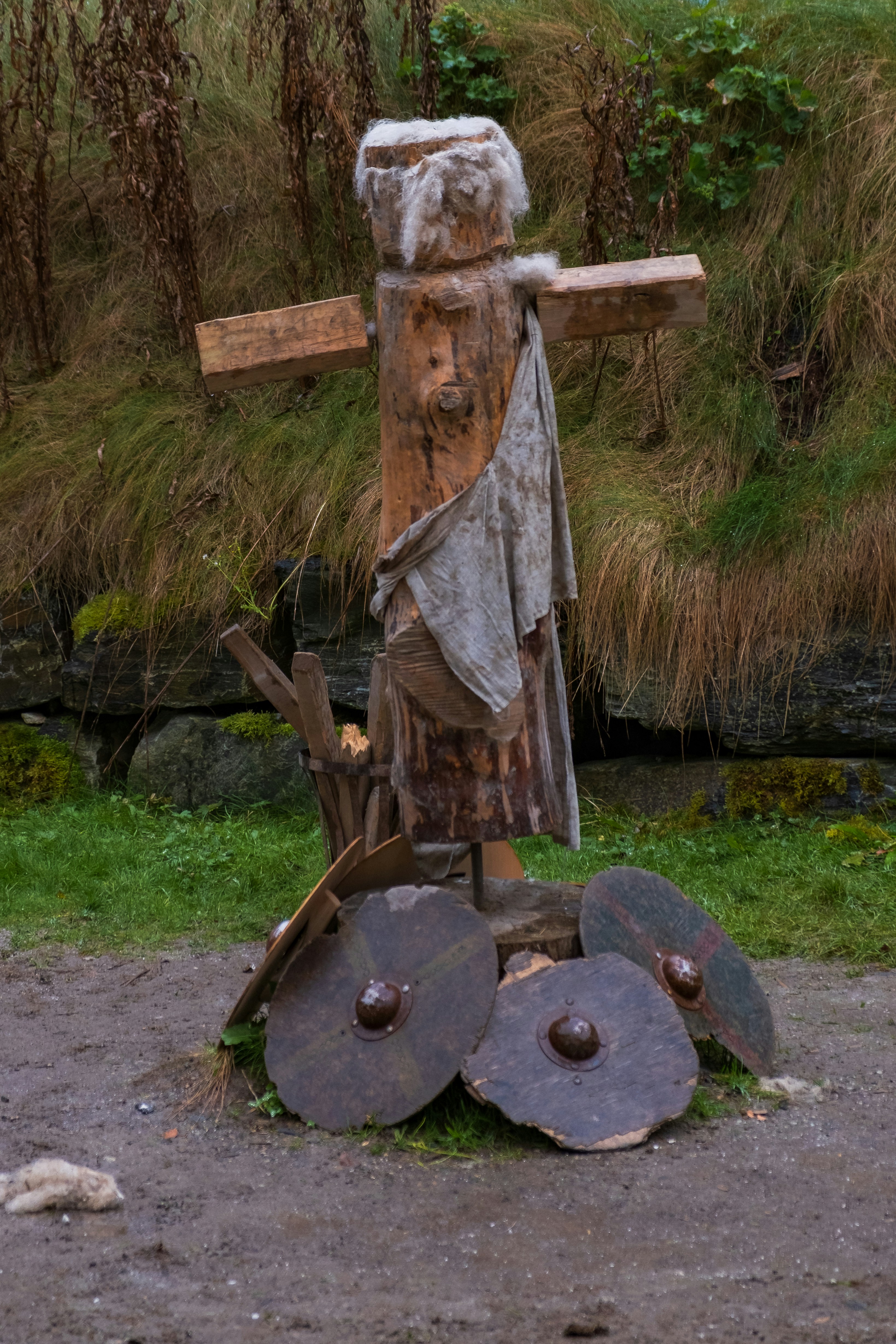 Weathered Crosswatcher: A Rustic Wood Sculpture Guarded by Shattered Shields