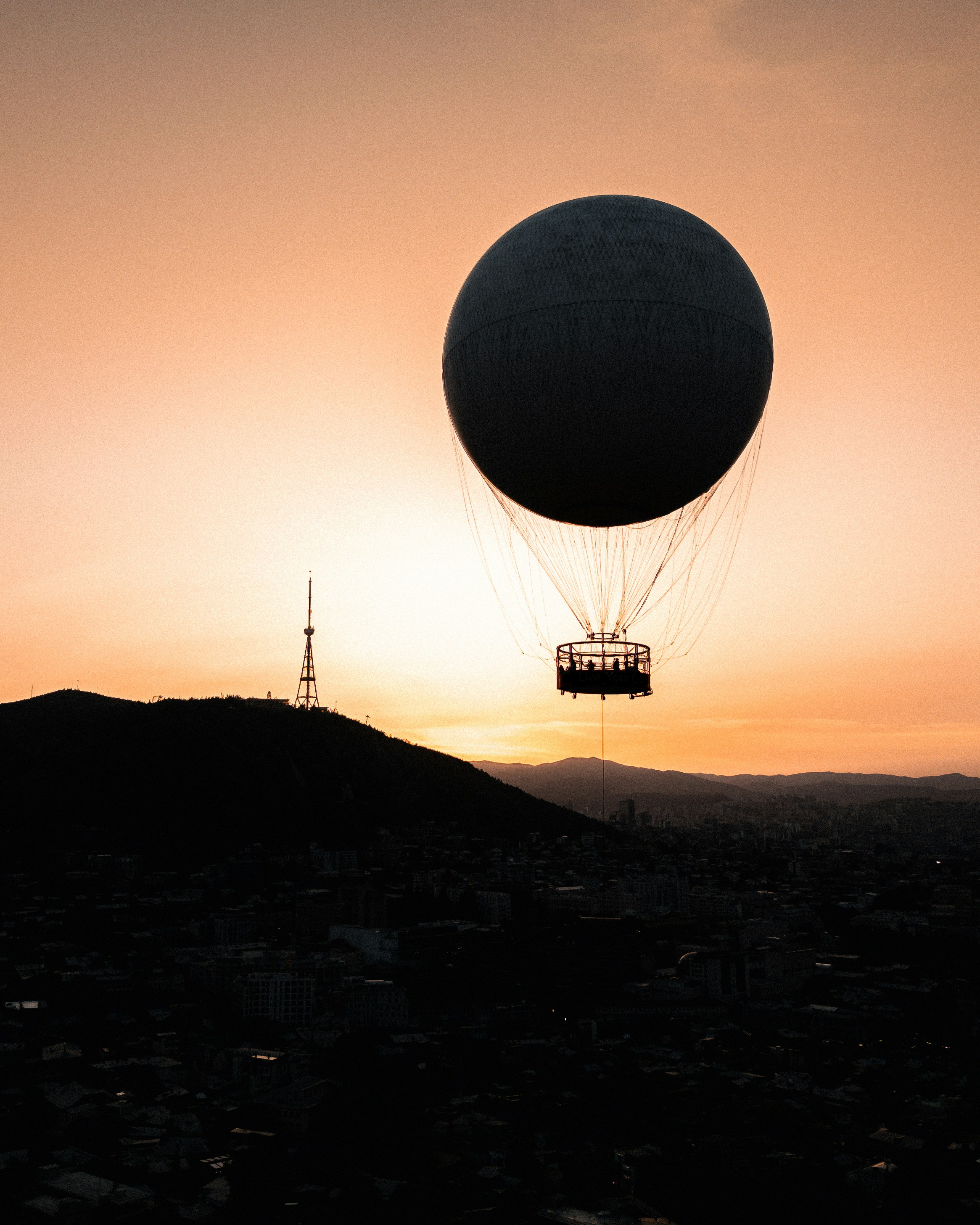 Sunset Lift: Balloon Silhouette Over City Ridge