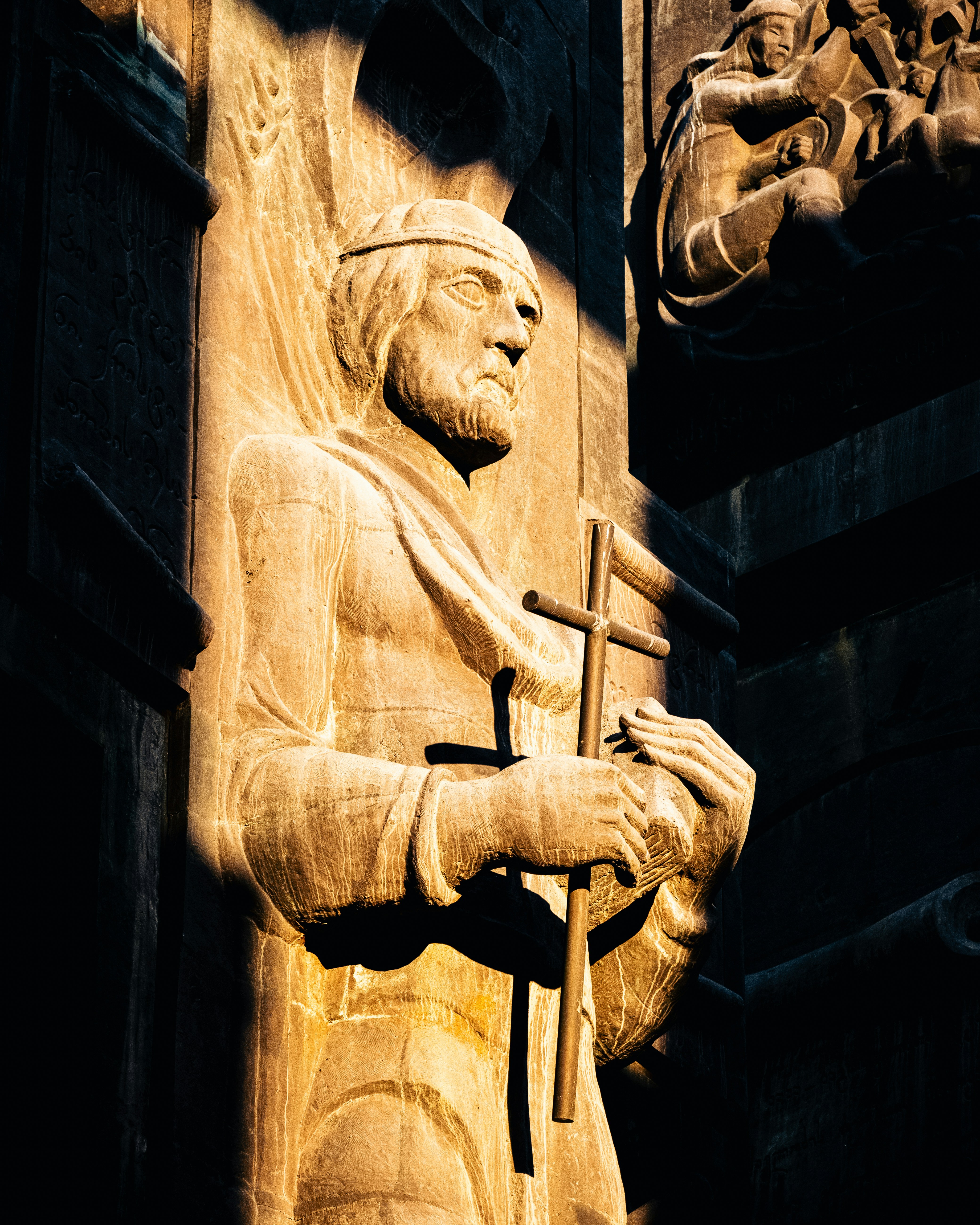 A statue of a man holding a cross next to a building photo – Free ...