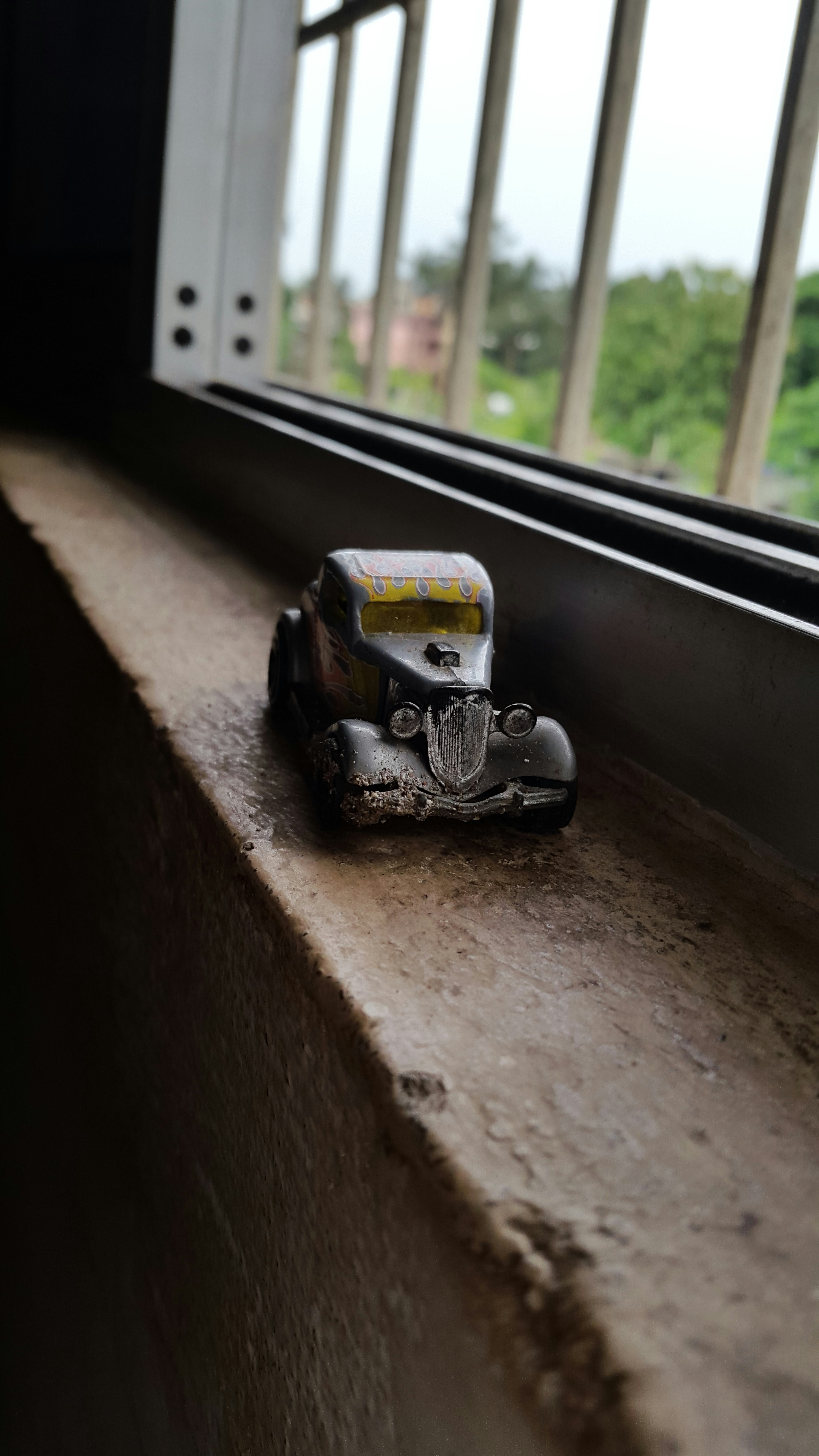 Rust and Resin: A Tiny Vintage Car on a Weathered Windowsill