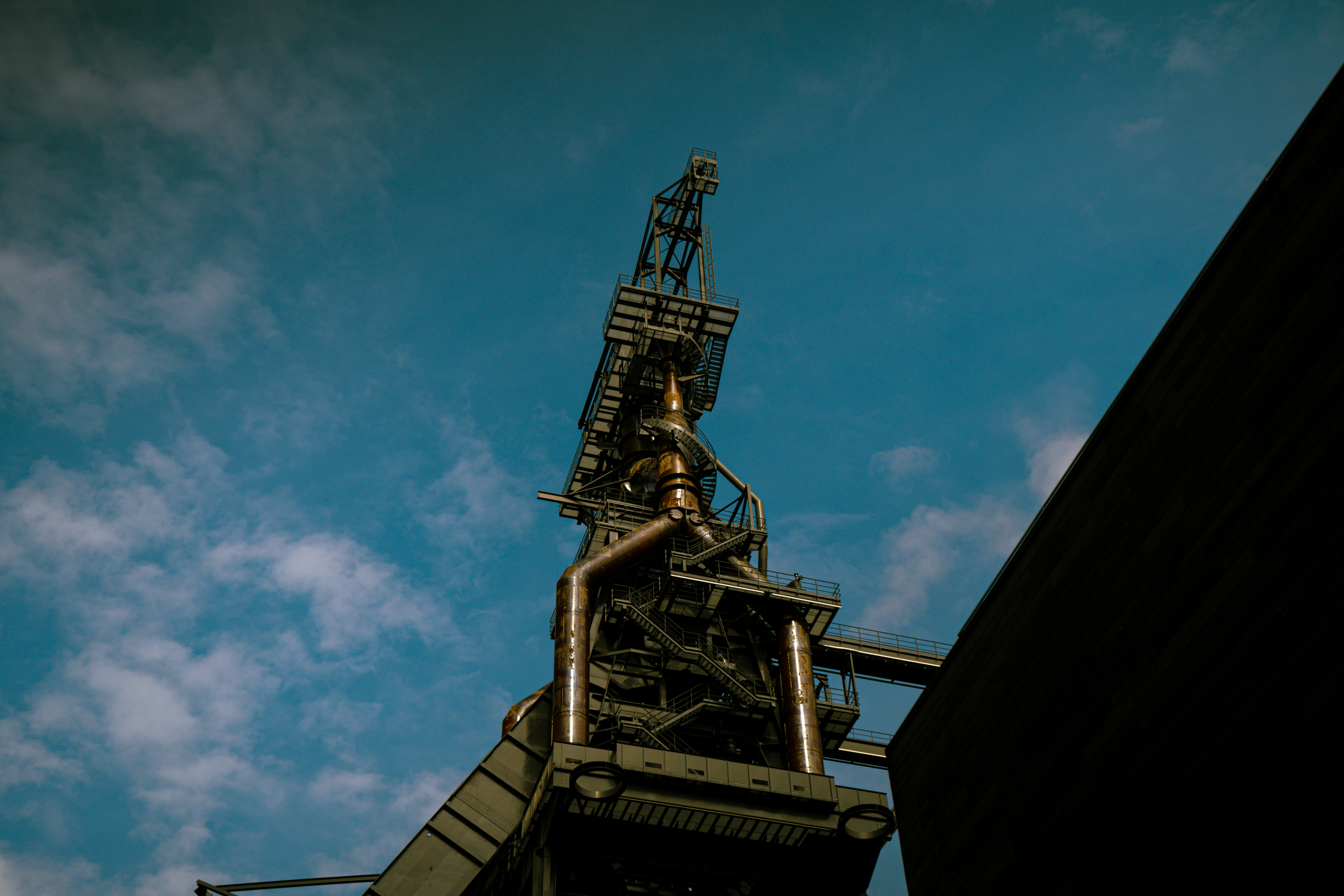 Imposing industrial structure reaching into a blue sky with scattered clouds.