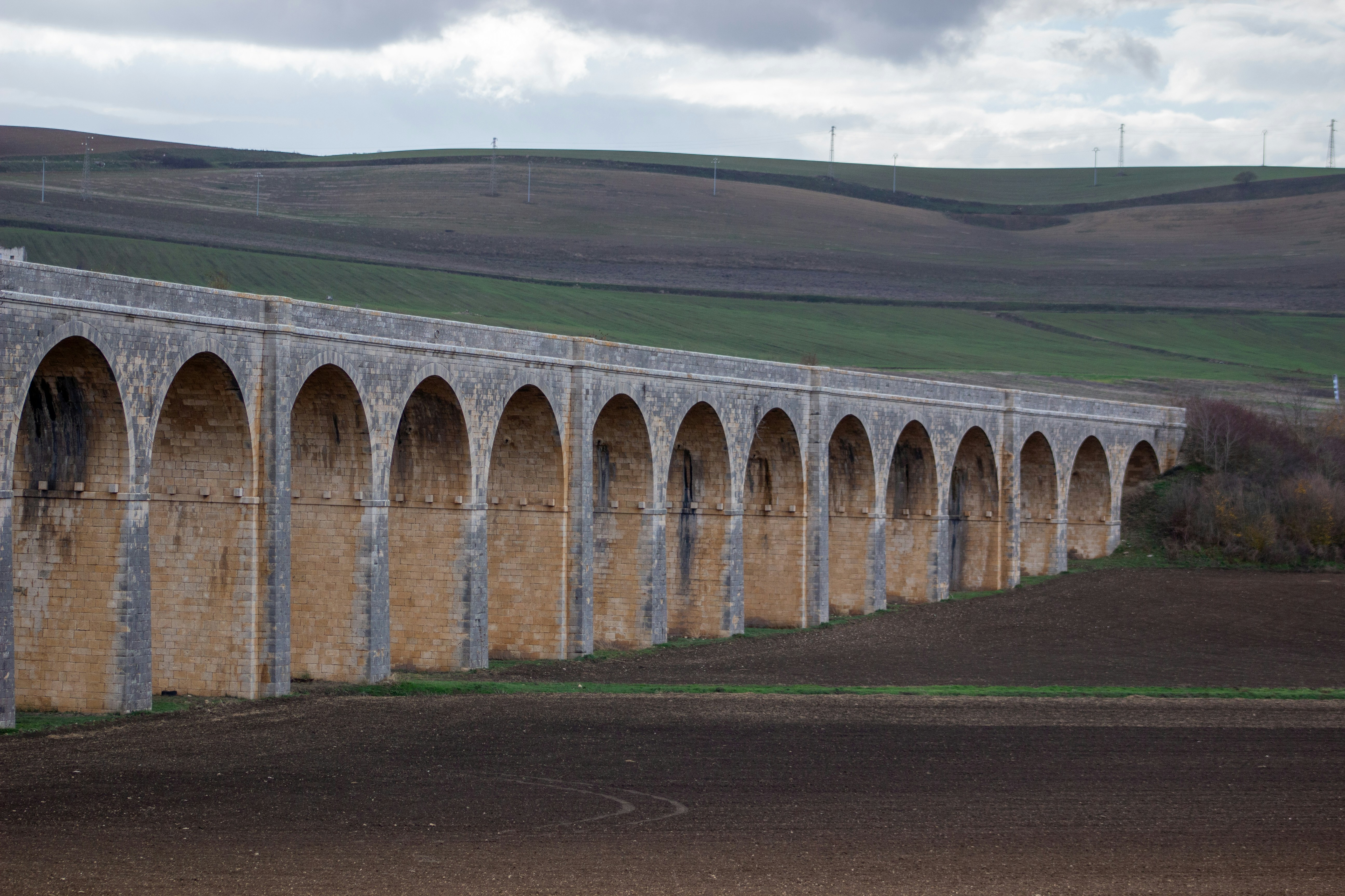 A large stone bridge with arches in the middle of a field photo – Free ...