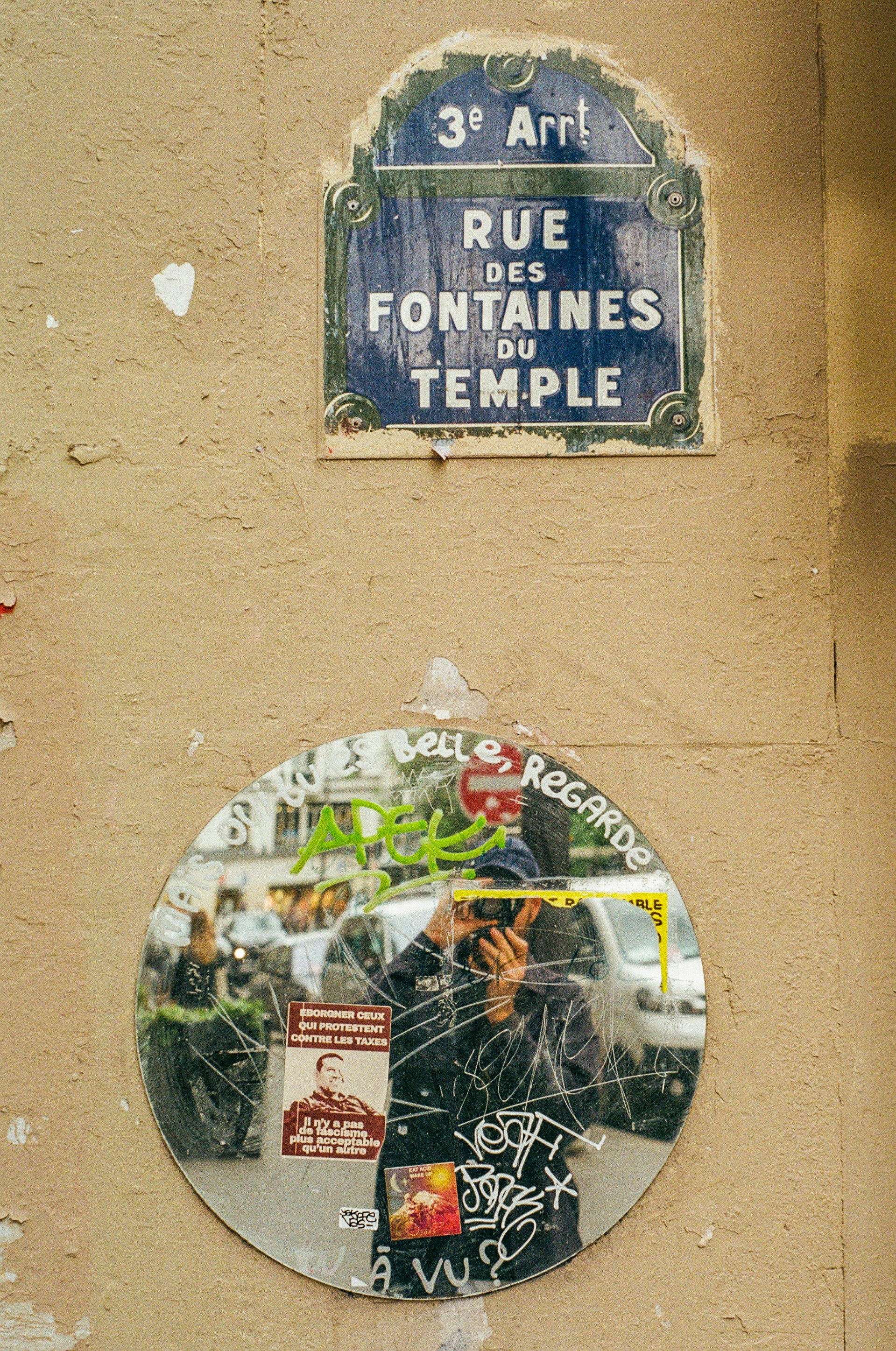 A mirror on the side of a building with graffiti on it