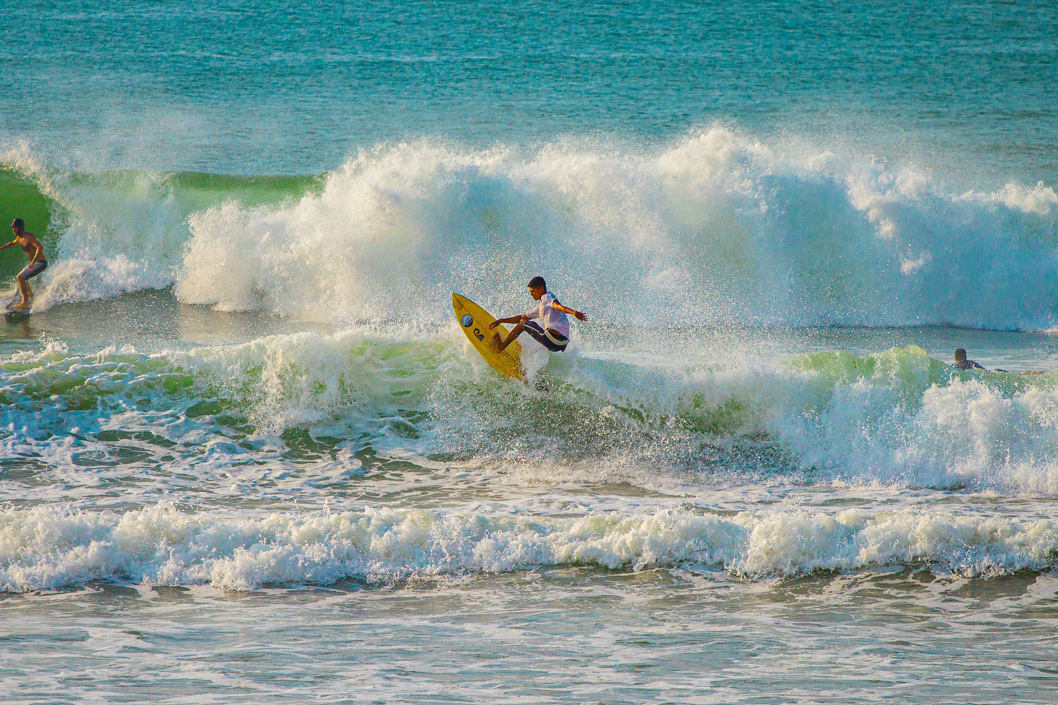 A group of people riding waves on top of surfboards photo – Free ...