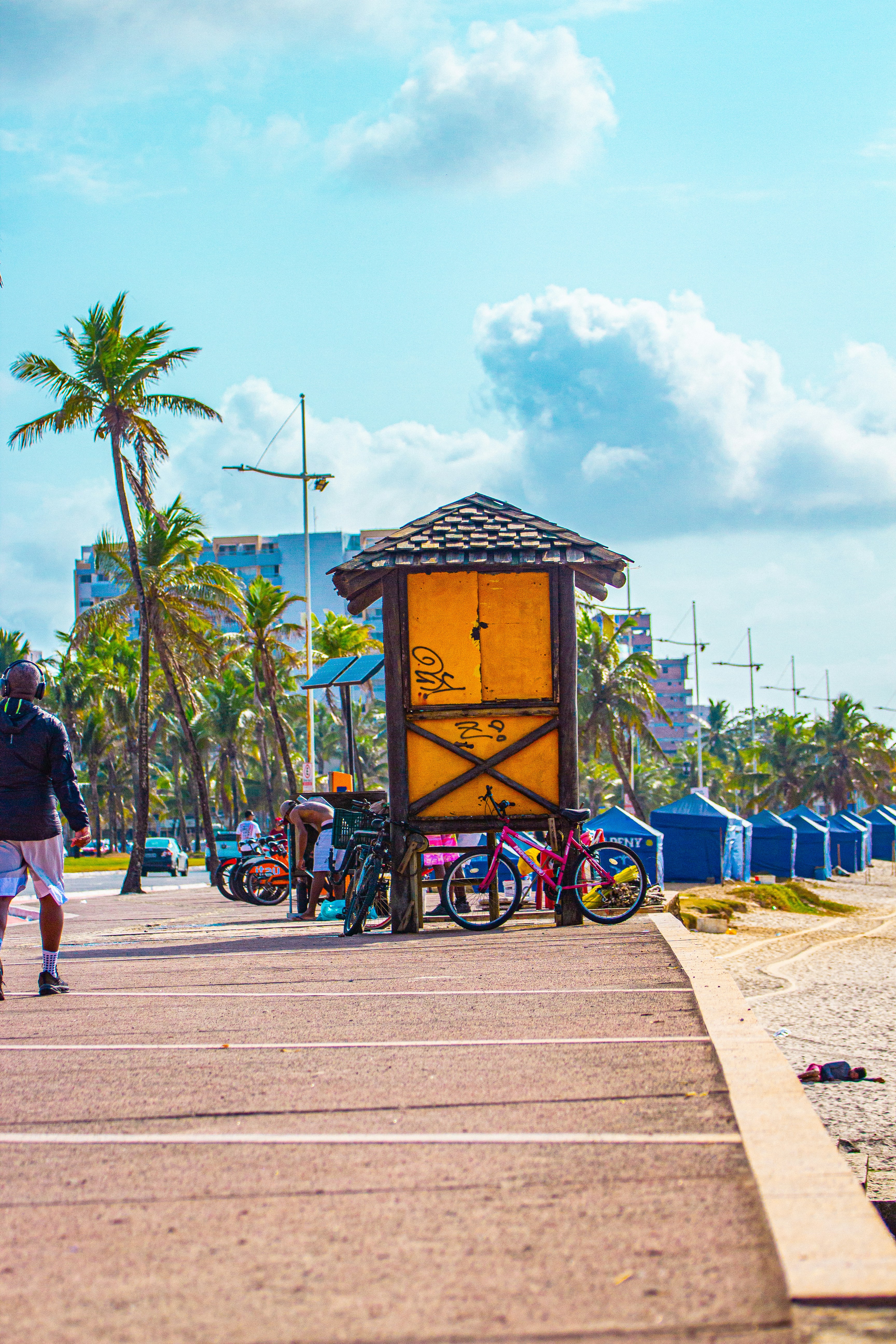 A man walking down a street next to a life guard tower