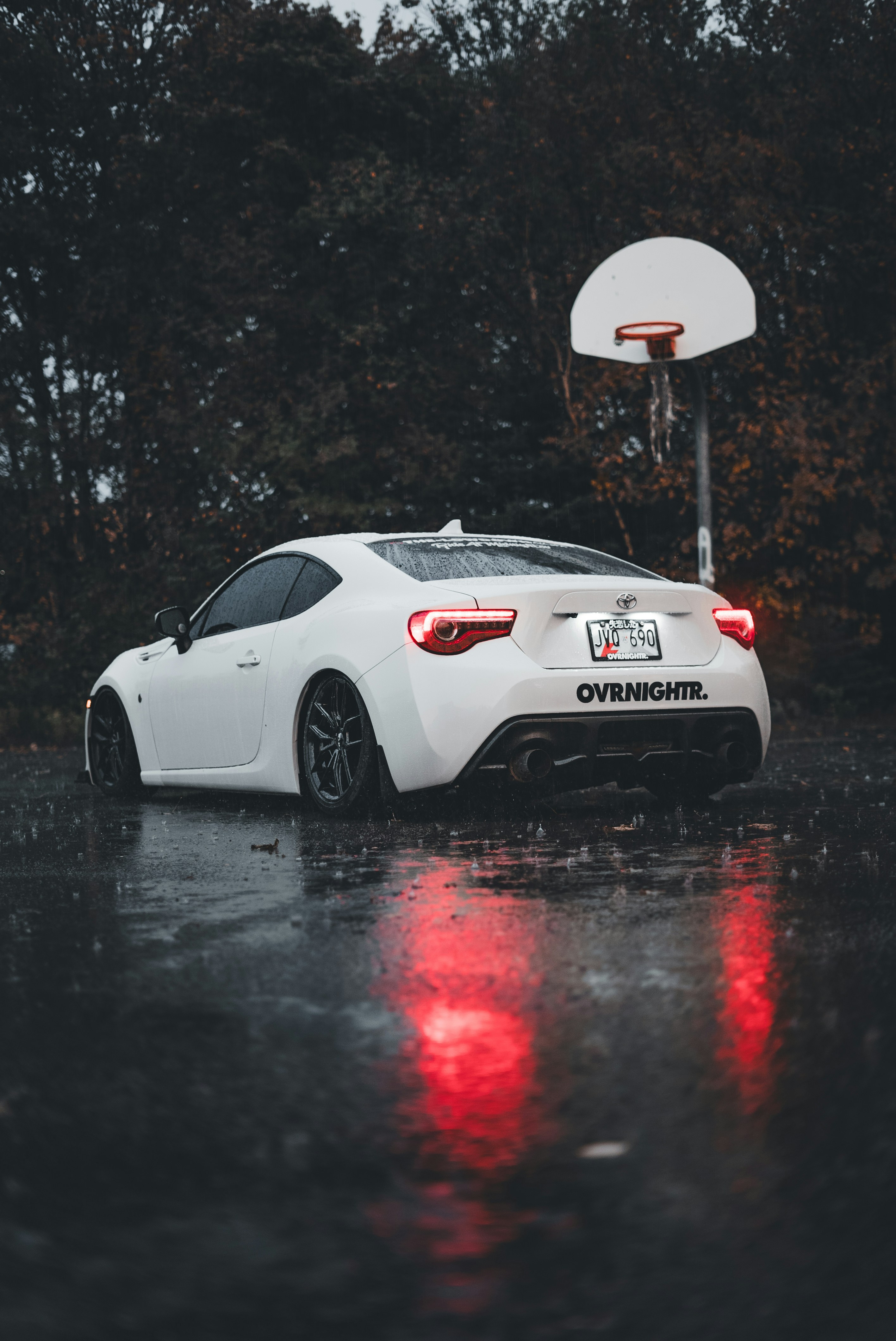 Backboard Noir: White Sports Coupe in Rain and Neon Reflections