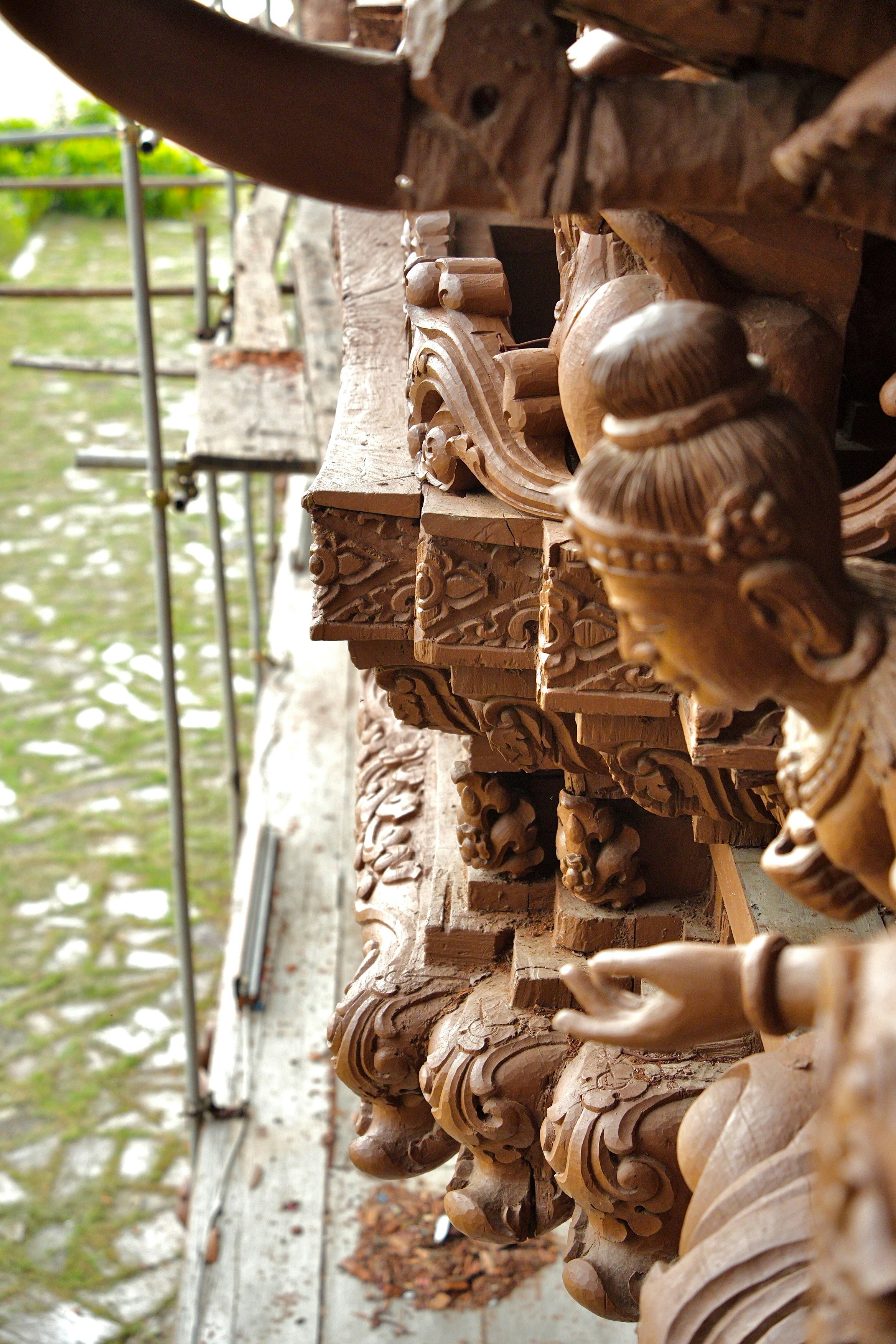 Riverside Frieze: Intricate Guardian Carving Framed by Scaffolding