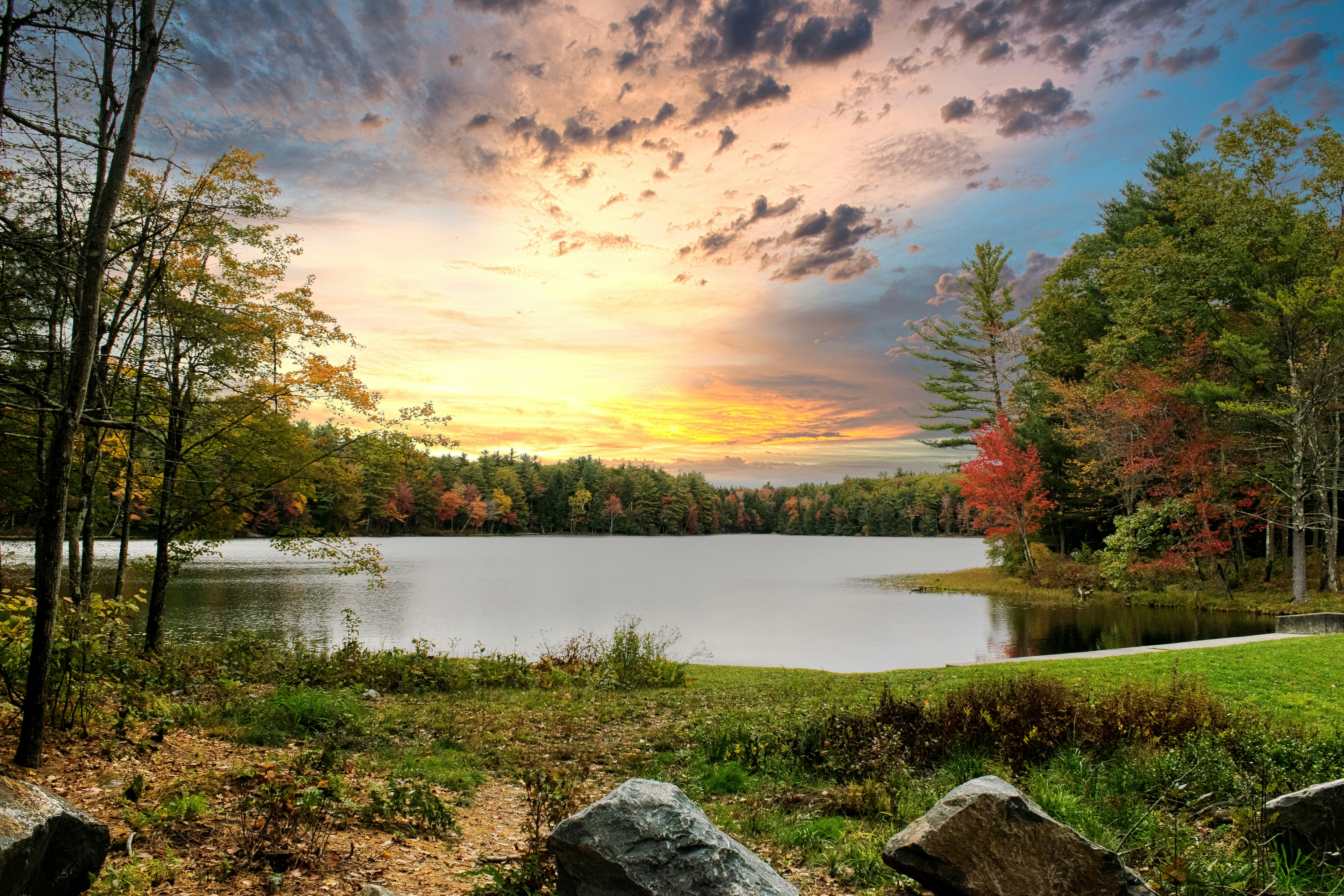 A beautiful sunset over a lake with rocks in the foreground photo ...