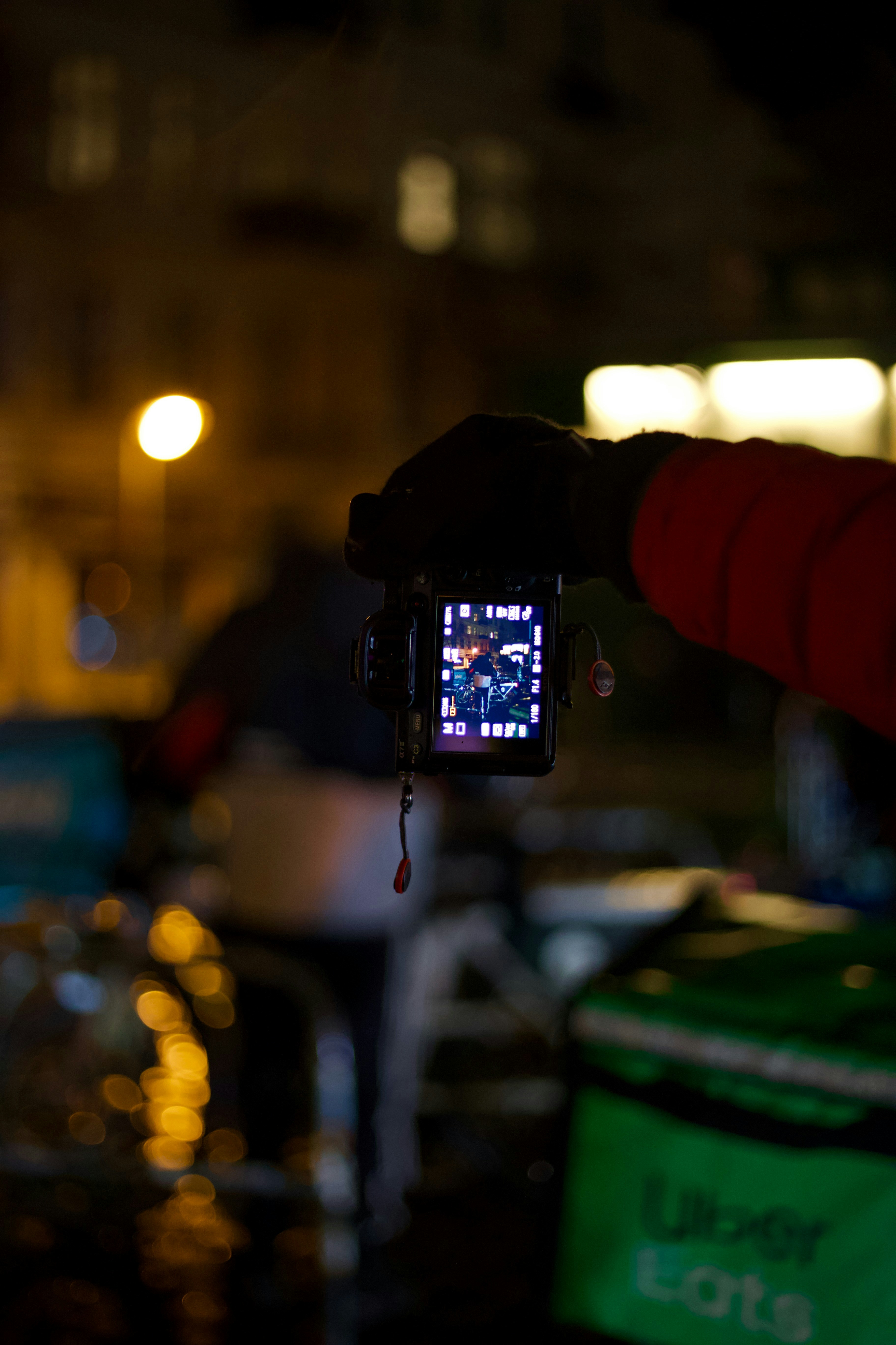 Nightframe in Hand: A handheld camera captures neon reflections on a rain-kissed street.