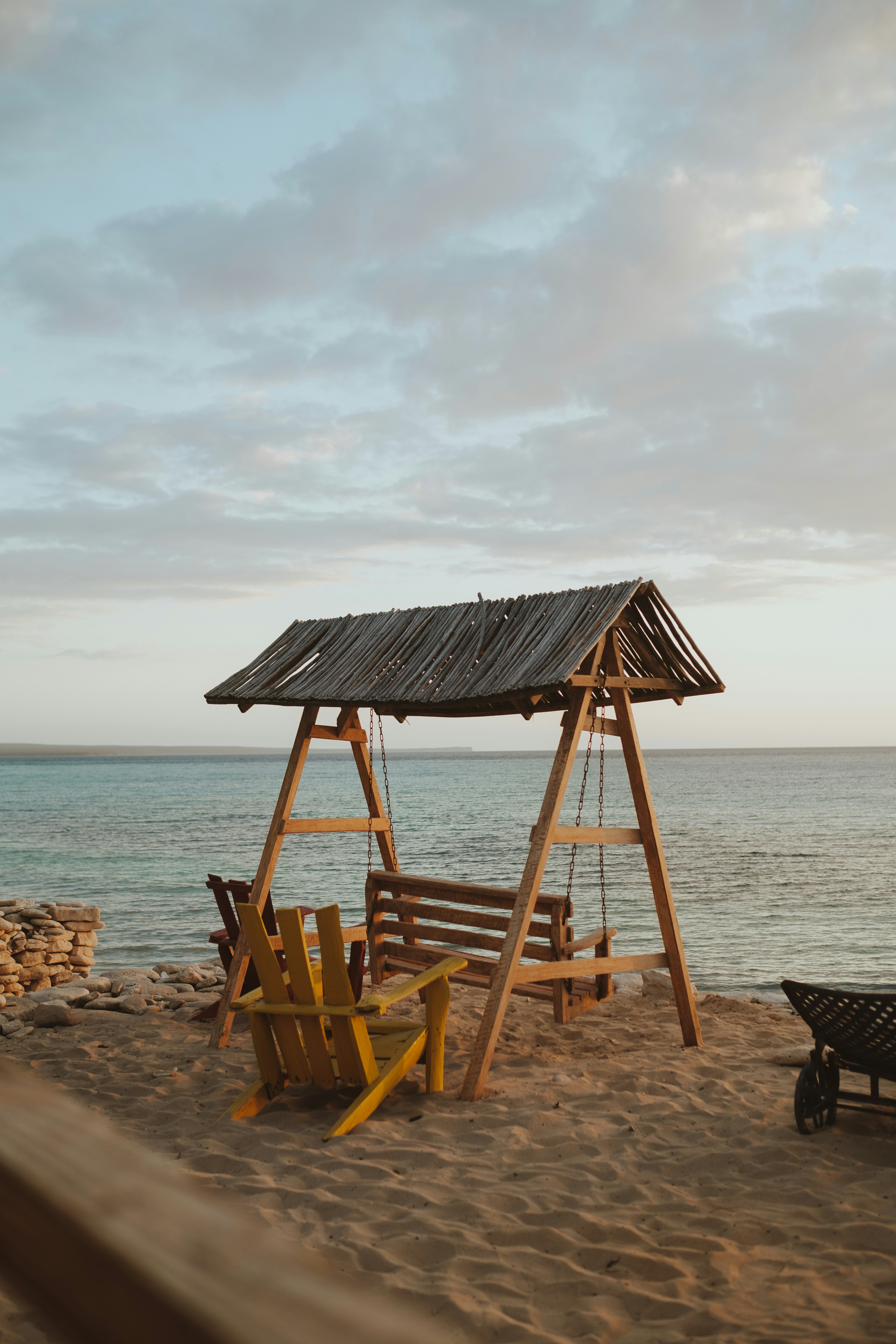 Sea-Whisper Swing: A Weathered Roof Over Quiet Sand