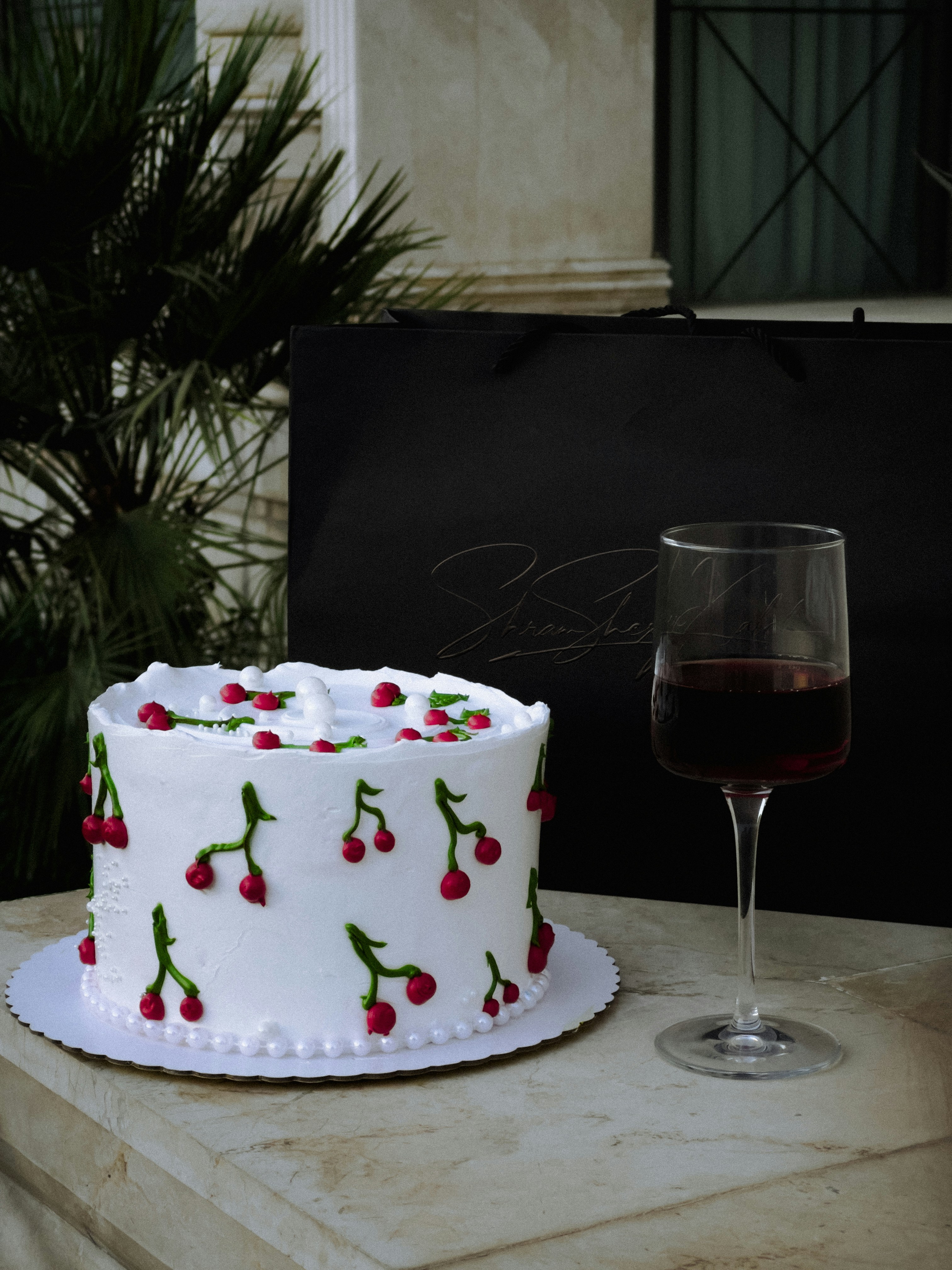 Cherry-Cushed Cake beside a Dark Gift