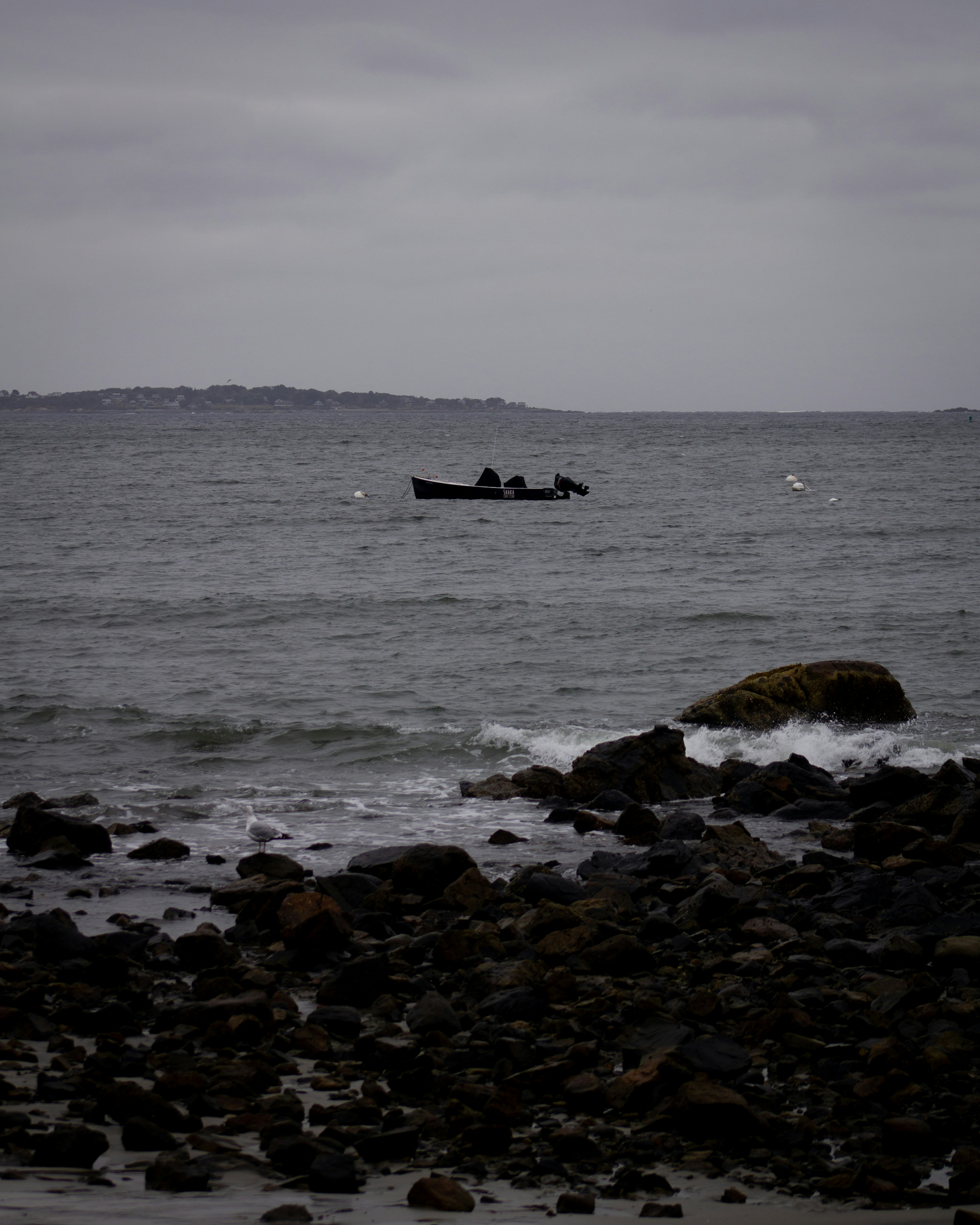 Muted Horizon, Lone Boat: A Quiet Seascape Amid Grey Skies