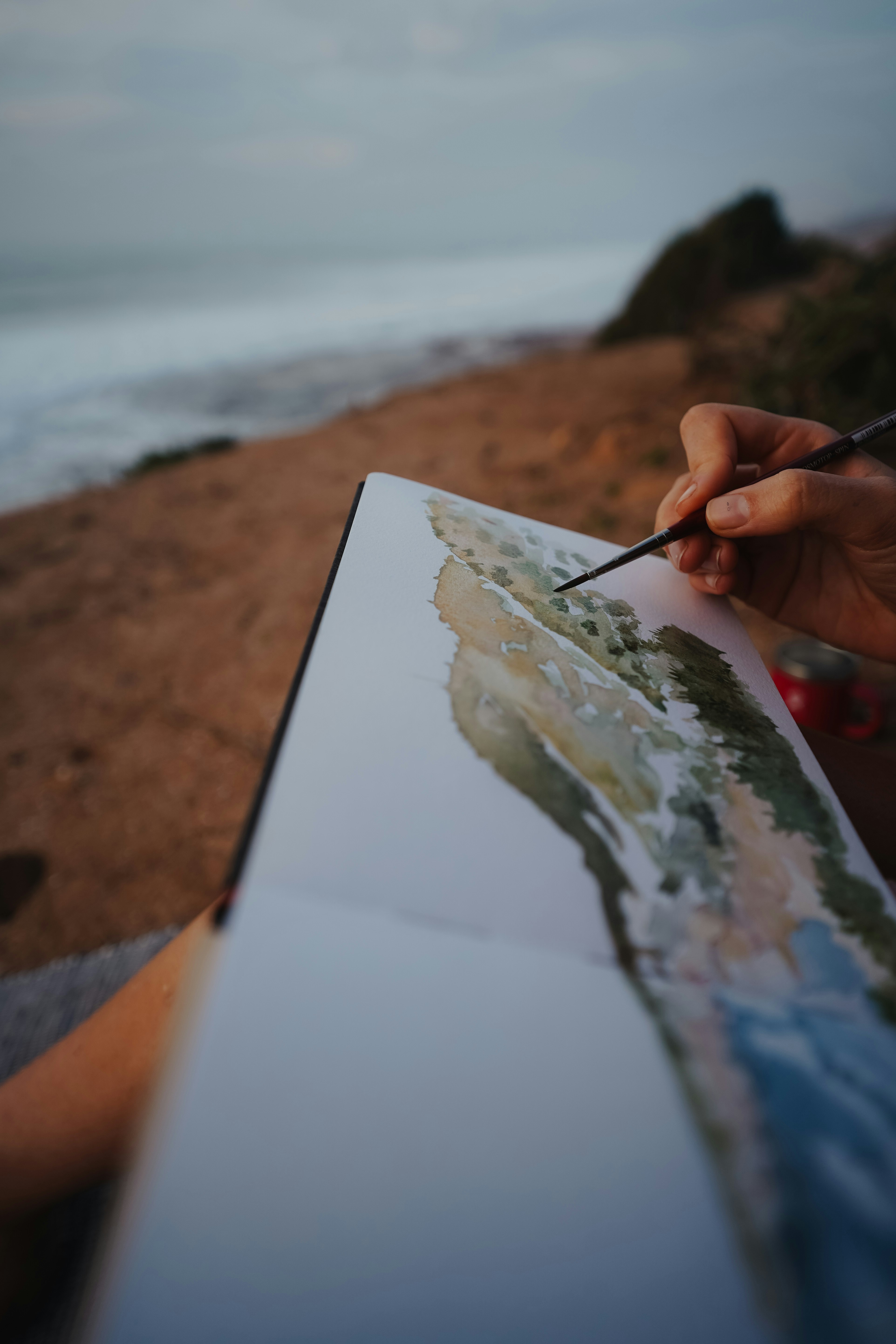 A person is painting a picture on the beach photo – Free Paint Image on ...