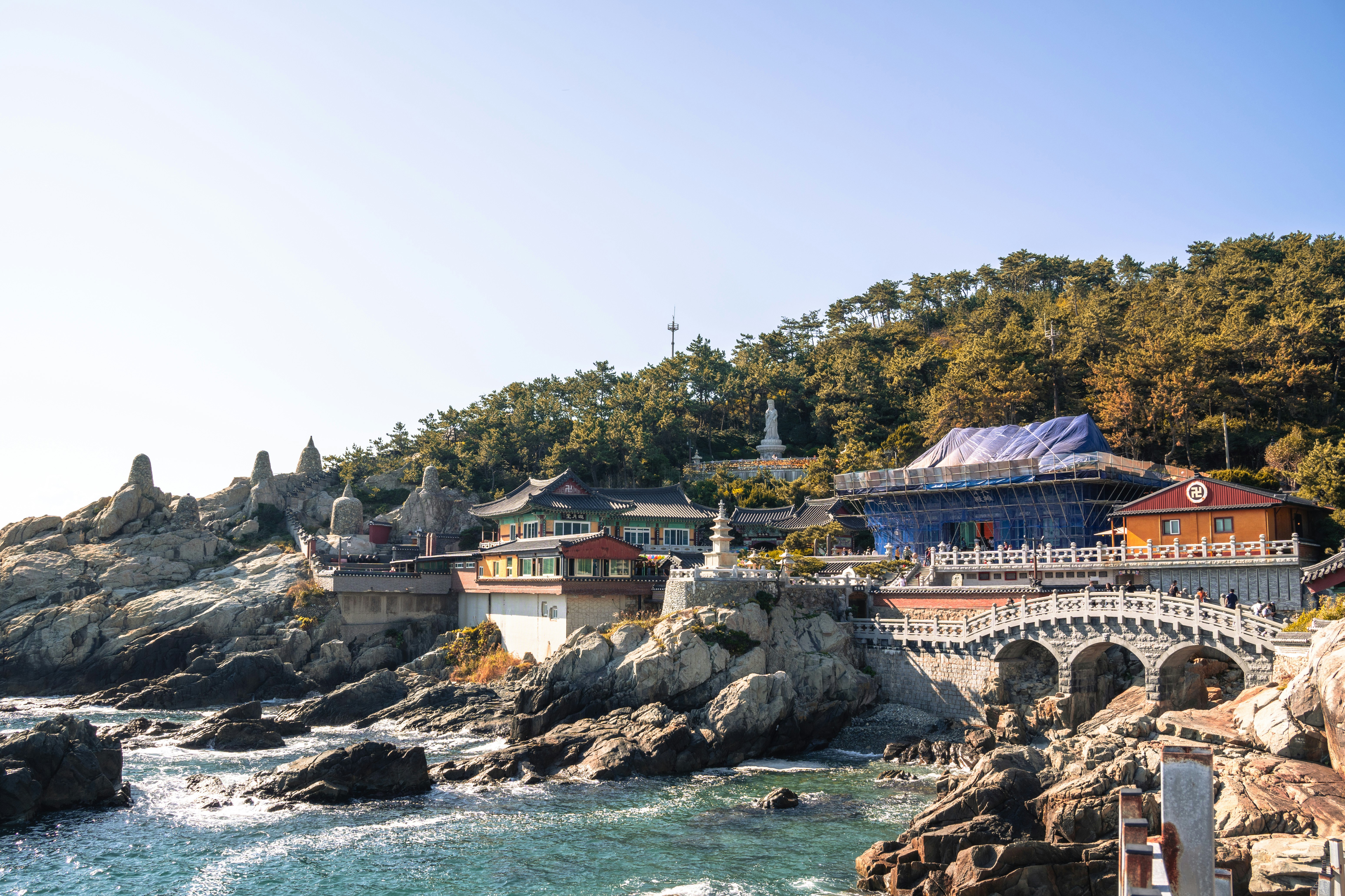A bridge over a body of water next to a lush green hillside photo ...