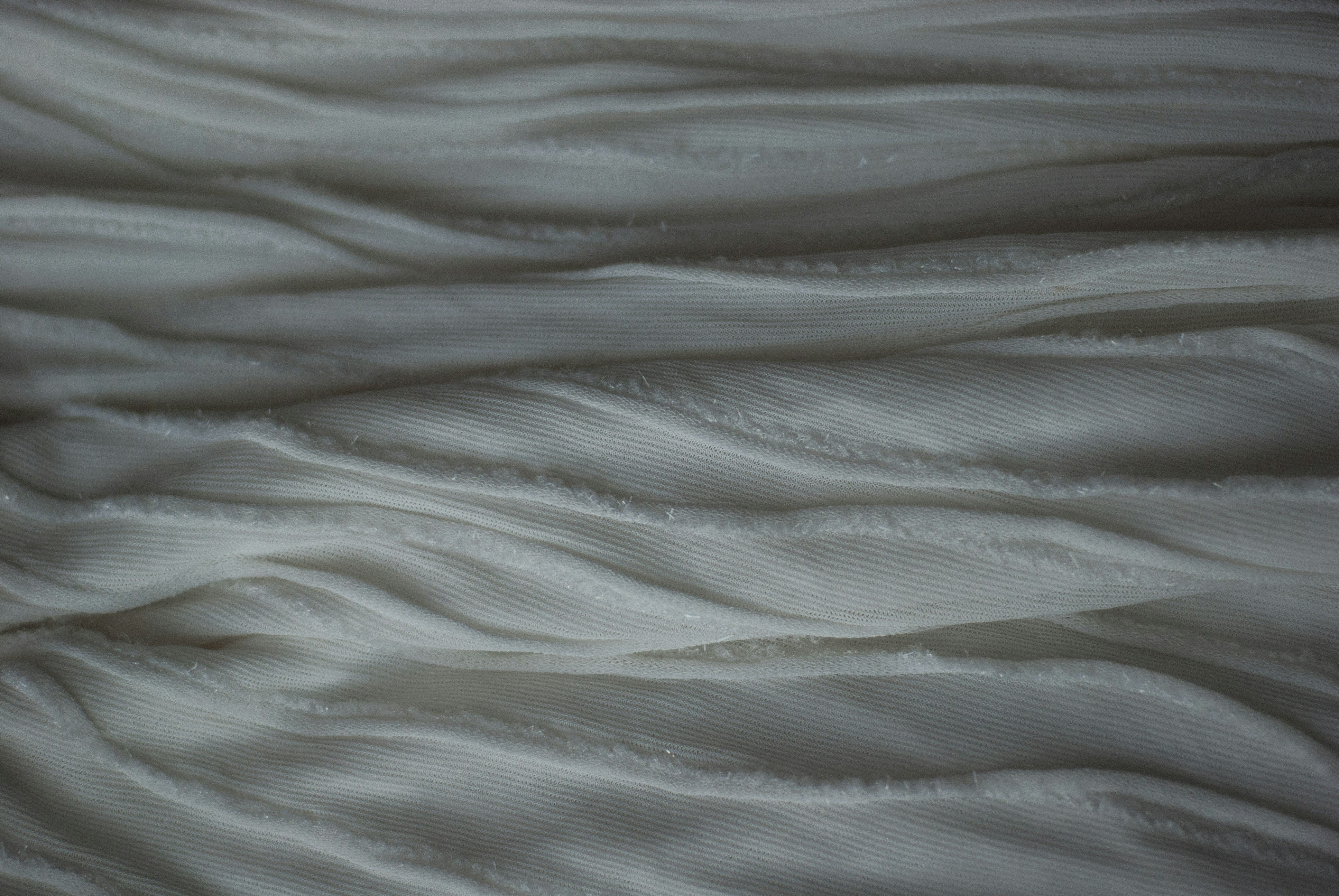 Background fabric texture. White jersey fabric with vertical folds and sun shadows.