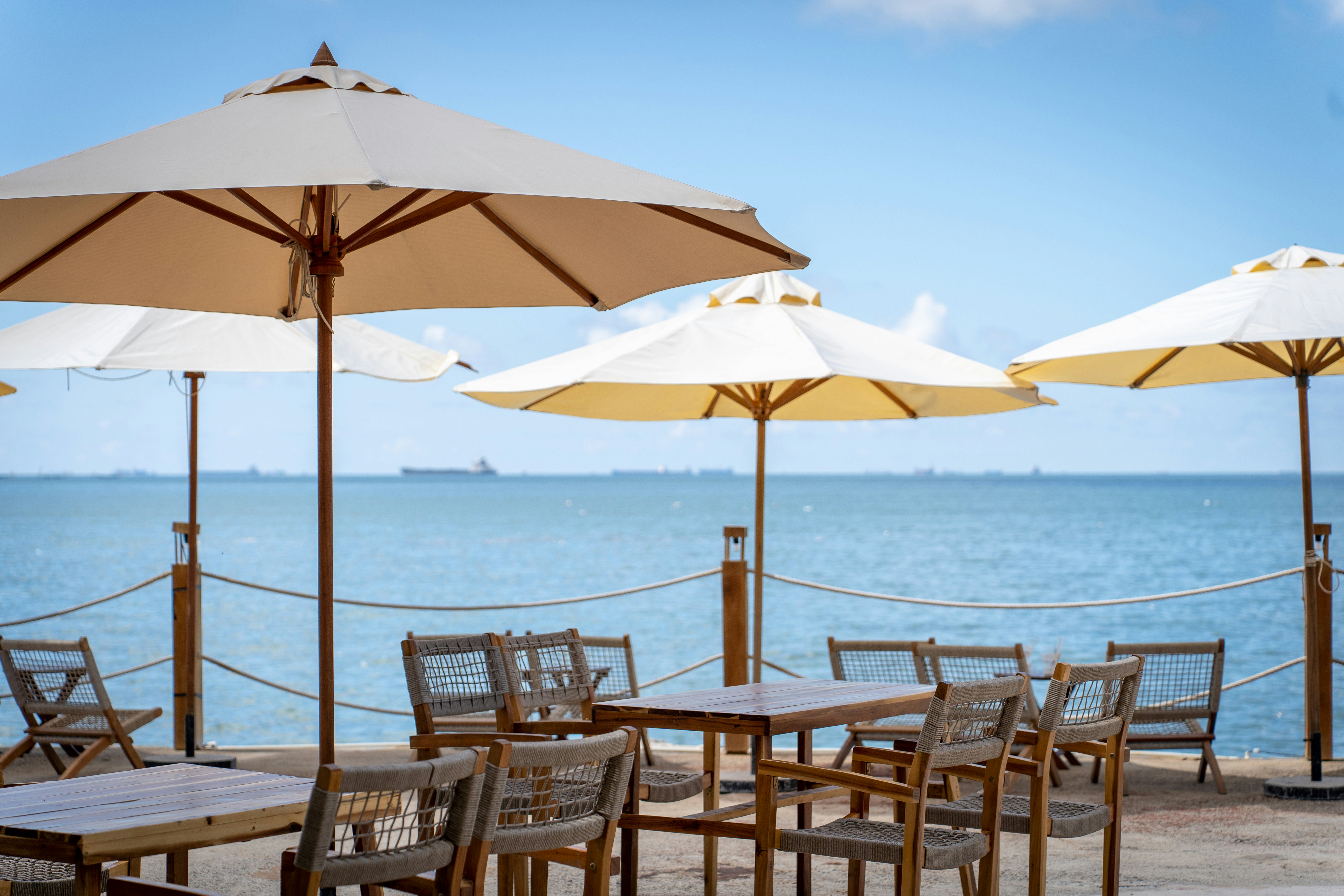 A group of tables and chairs with umbrellas over them photo – Free ...