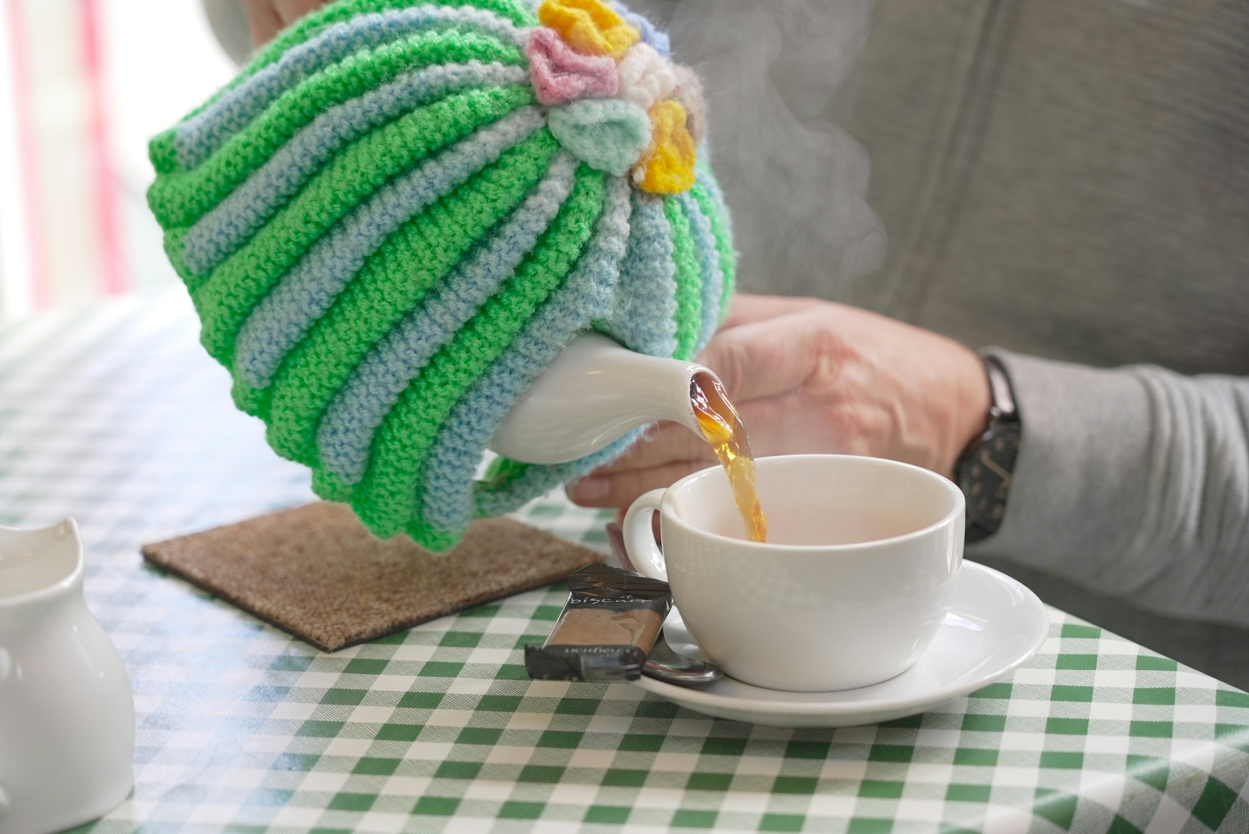 Steam-Scented Pour: A Cozy Tea Moment Under a Plush Green Cover