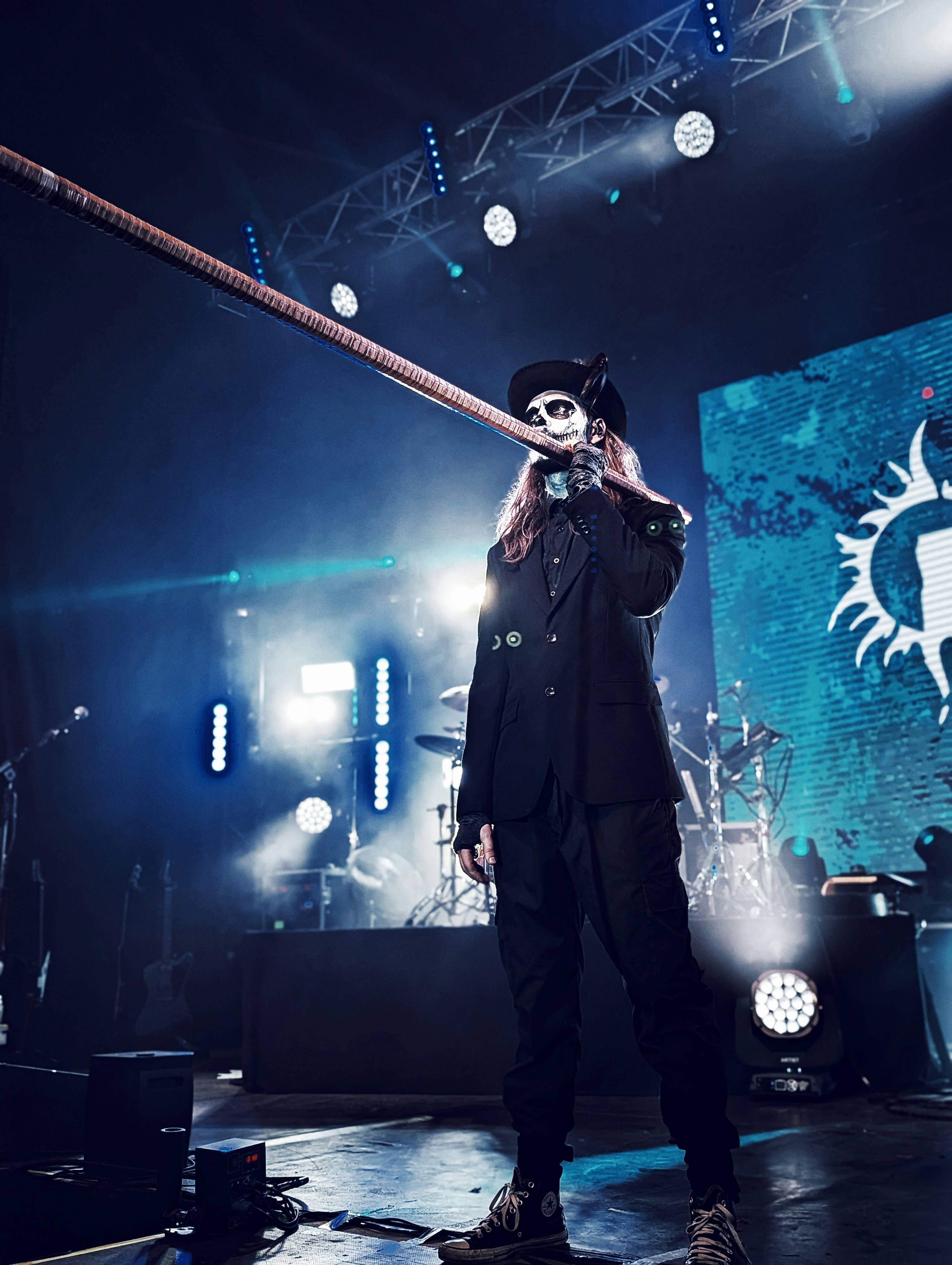 Masked Maestro on a Neon-Blue Stage with a Guitar Slung Across the Shoulder