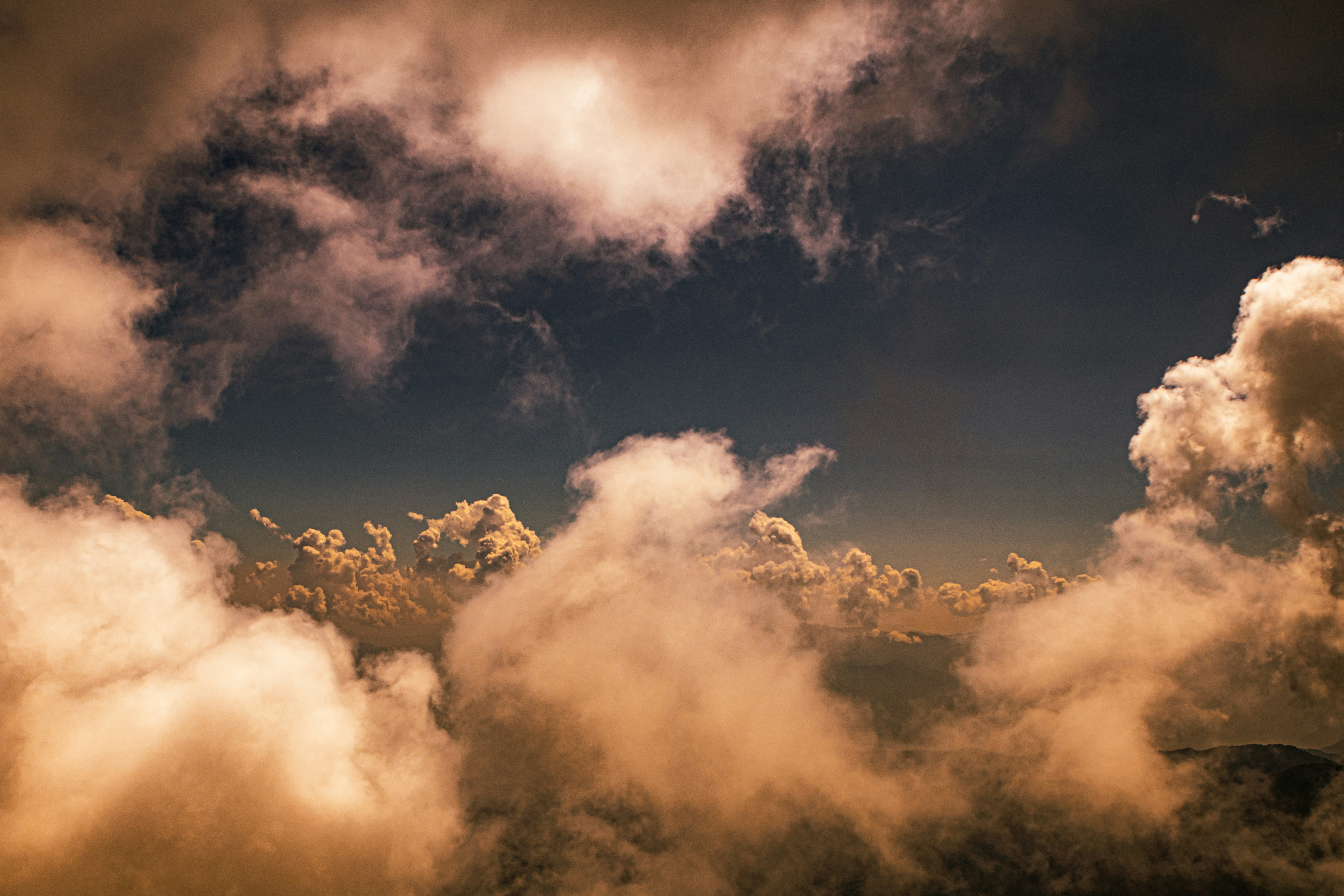 Dramatic cloud formations illuminated by soft sunlight, creating a mystical atmosphere in the sky.
