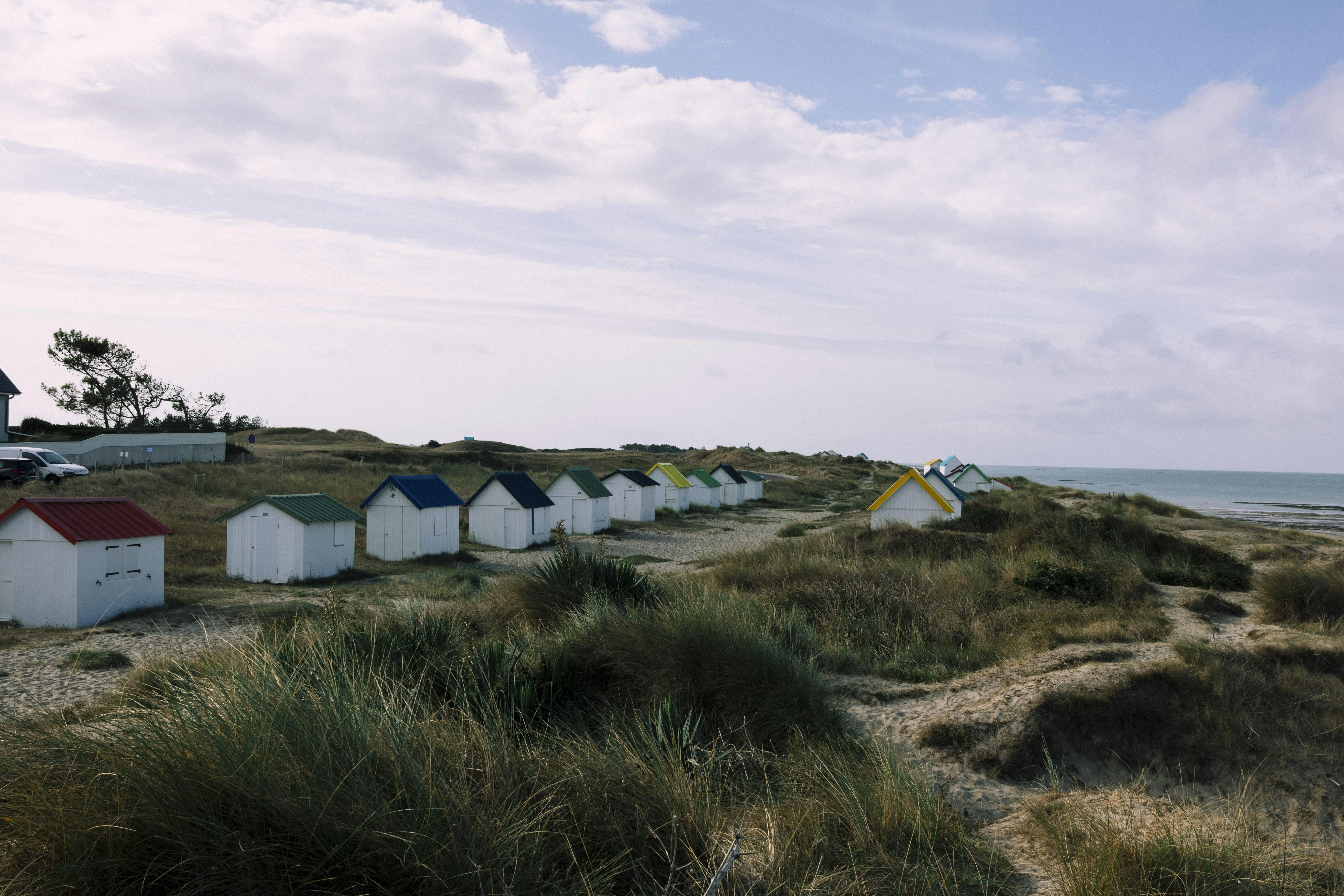A row of beach huts sitting on top of a sandy beach photo – Free ...