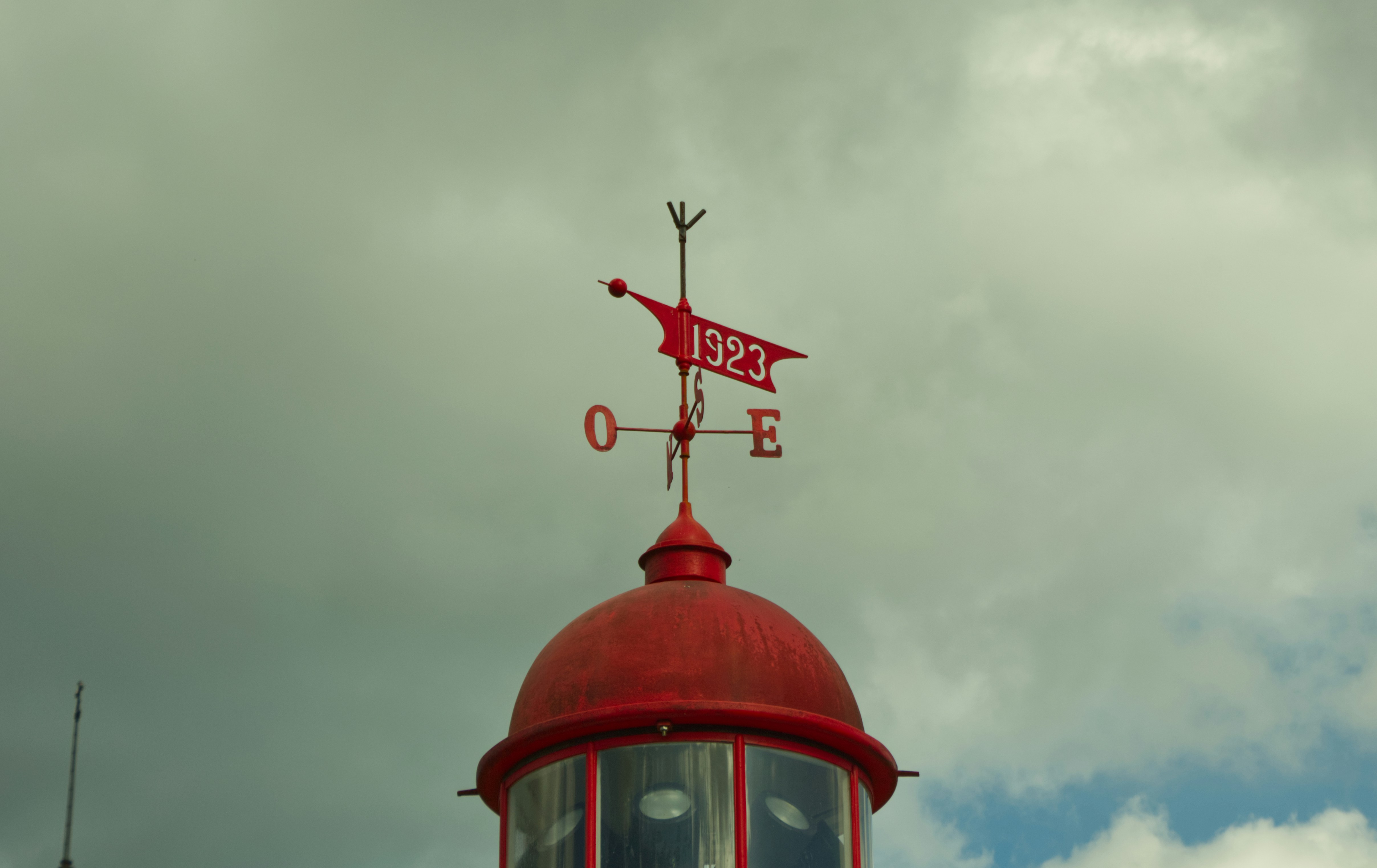 Historic Red Weather Vane Against Stormy Skies