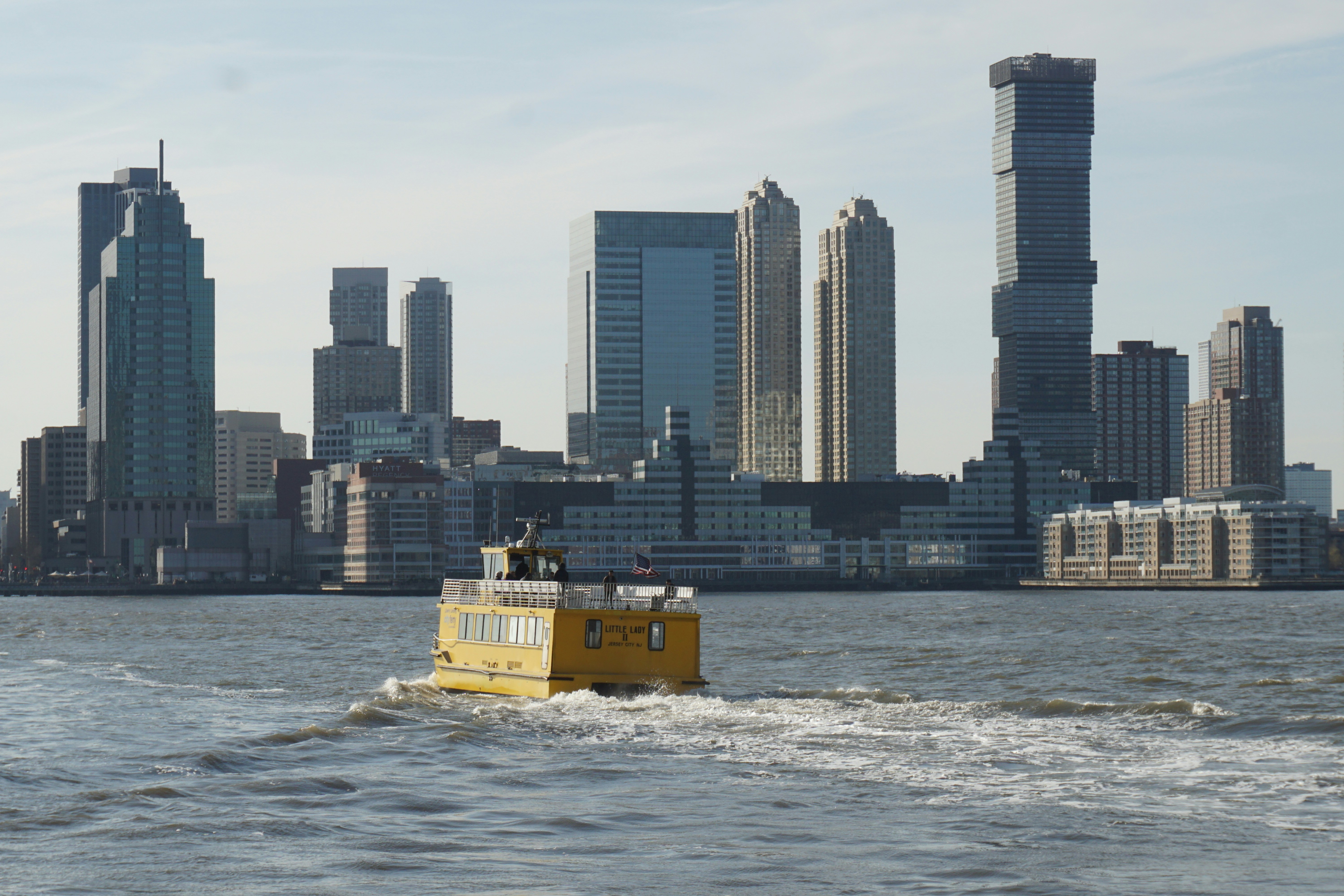 Yellow Ferry Skims the River Under a Modern Skyline
